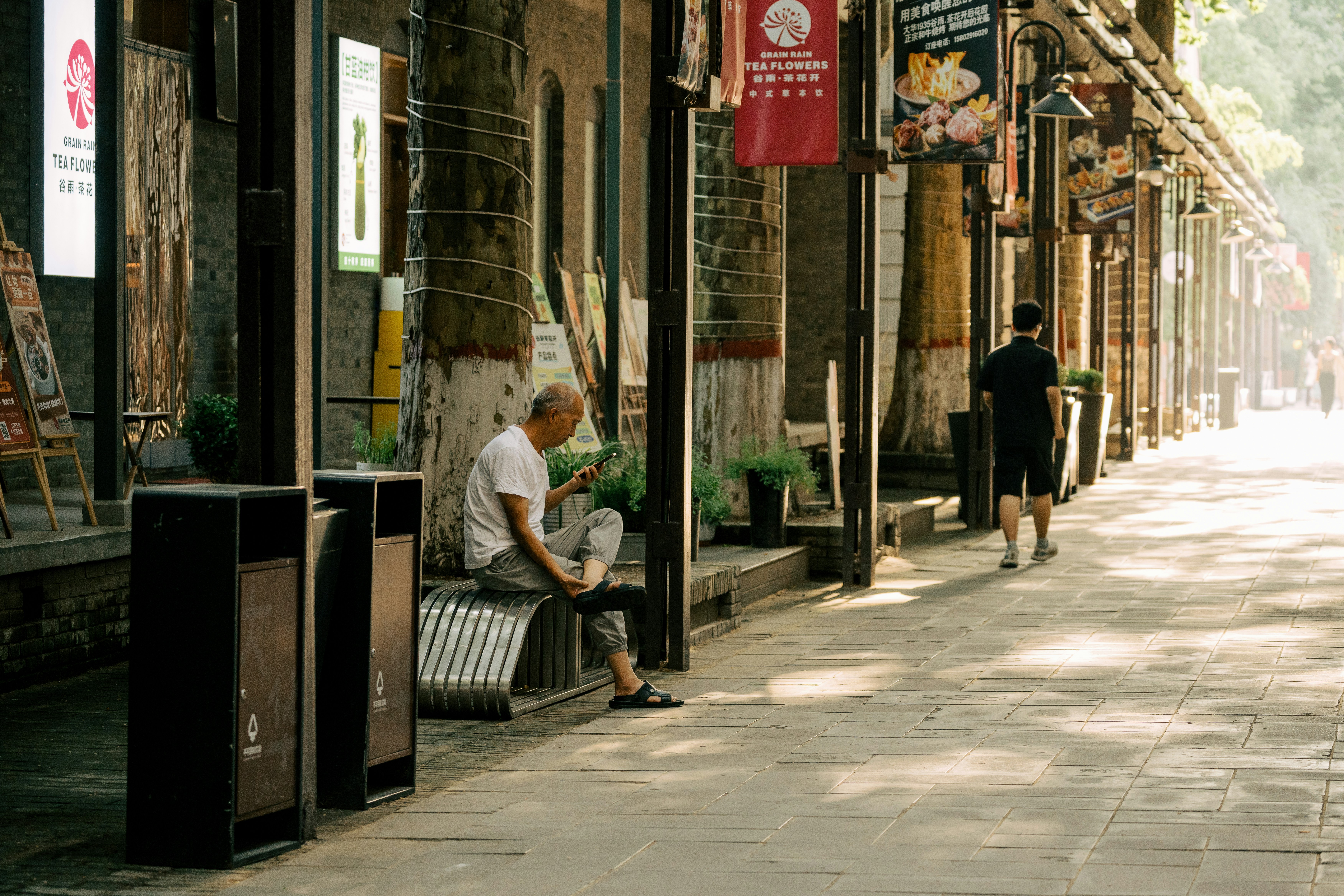 Quiet Corner: An Elderly Seated Man Beneath Shaded Alley Mulities