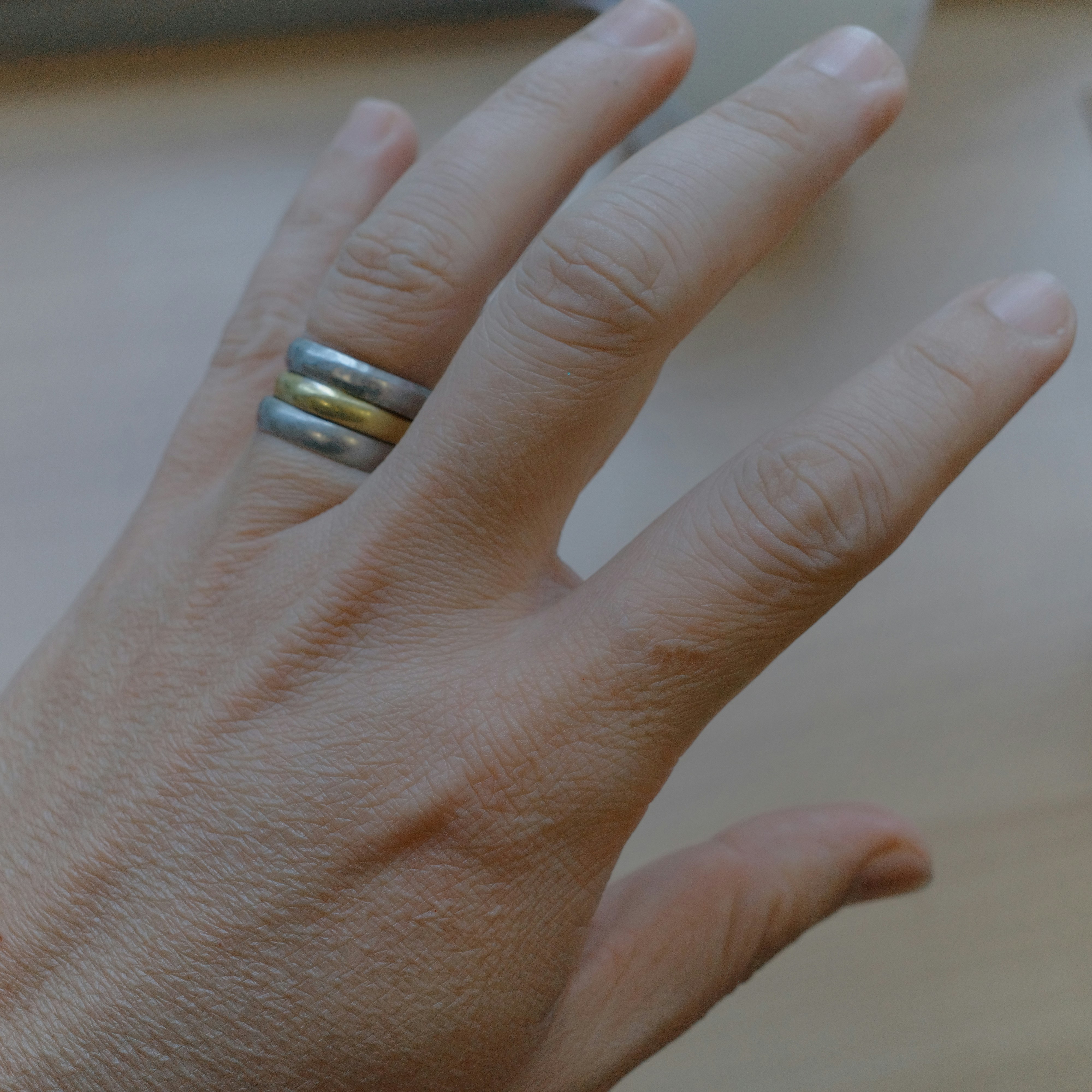 Close-up of a ringed hand: subtle textures and metallic bands in soft light