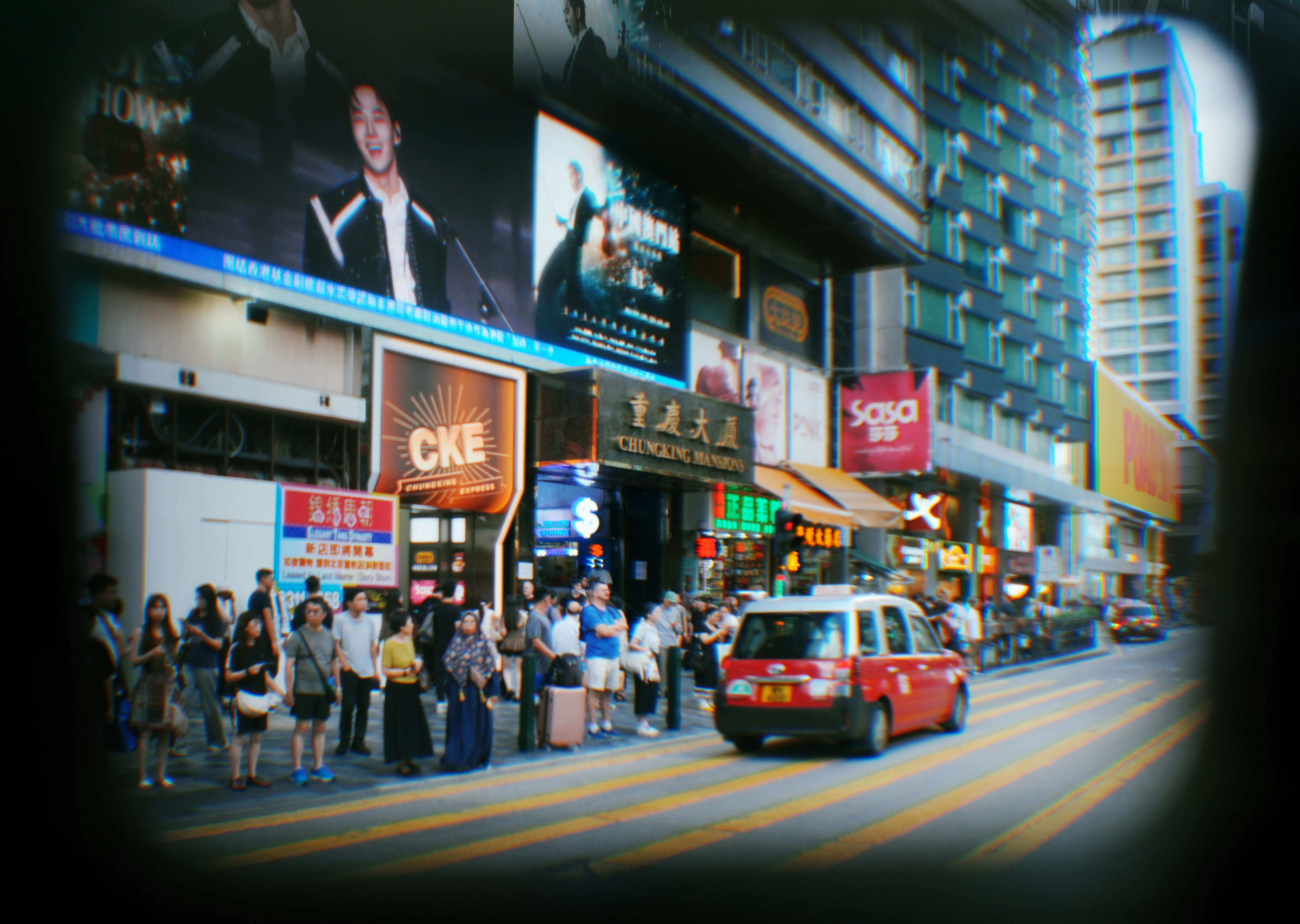 City Street Pulse: Crowd, Taxi, and Neon Beneath a Veil of Telephoto Blur