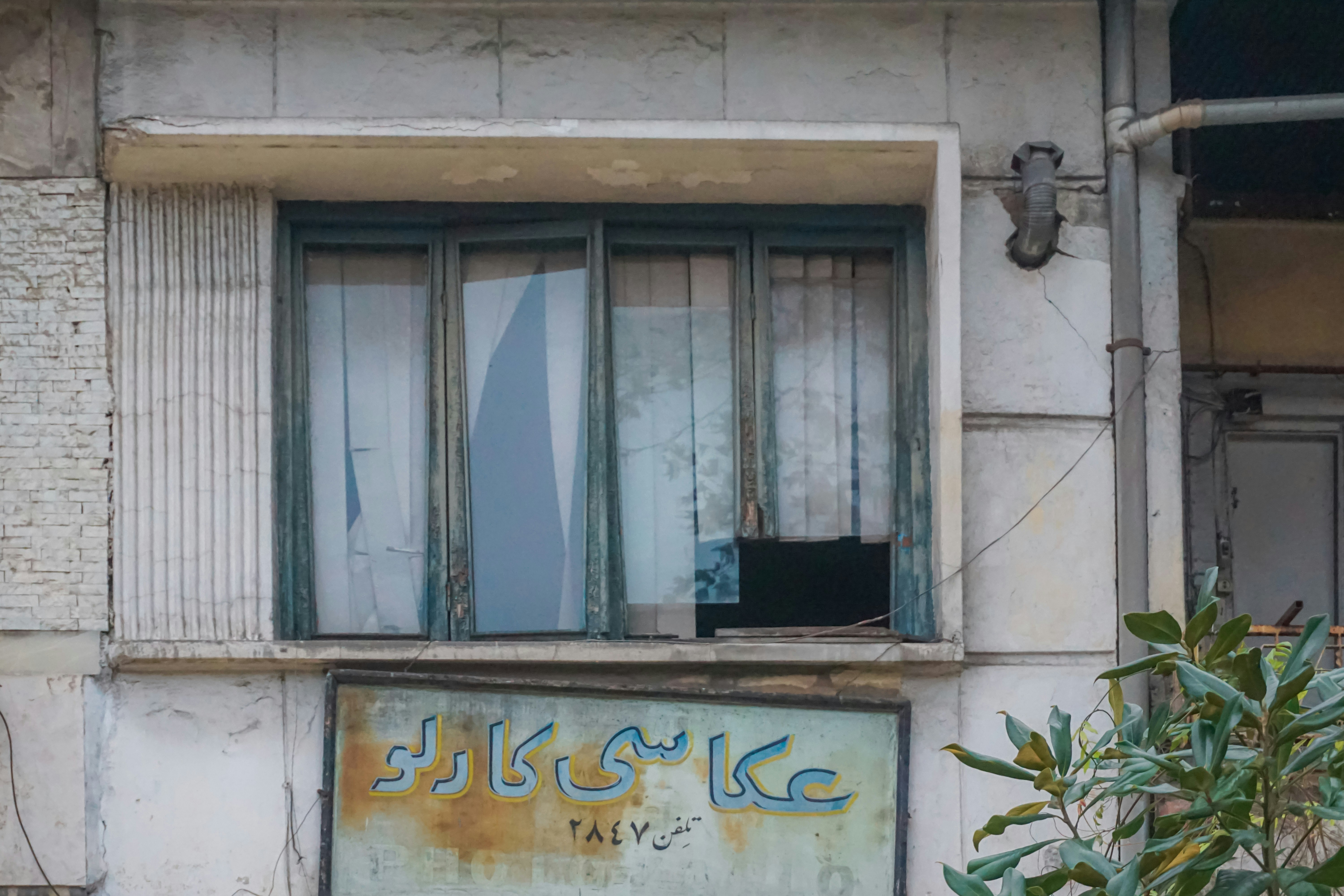 Abraded Window Echoes the Street Sign of a Distant Market