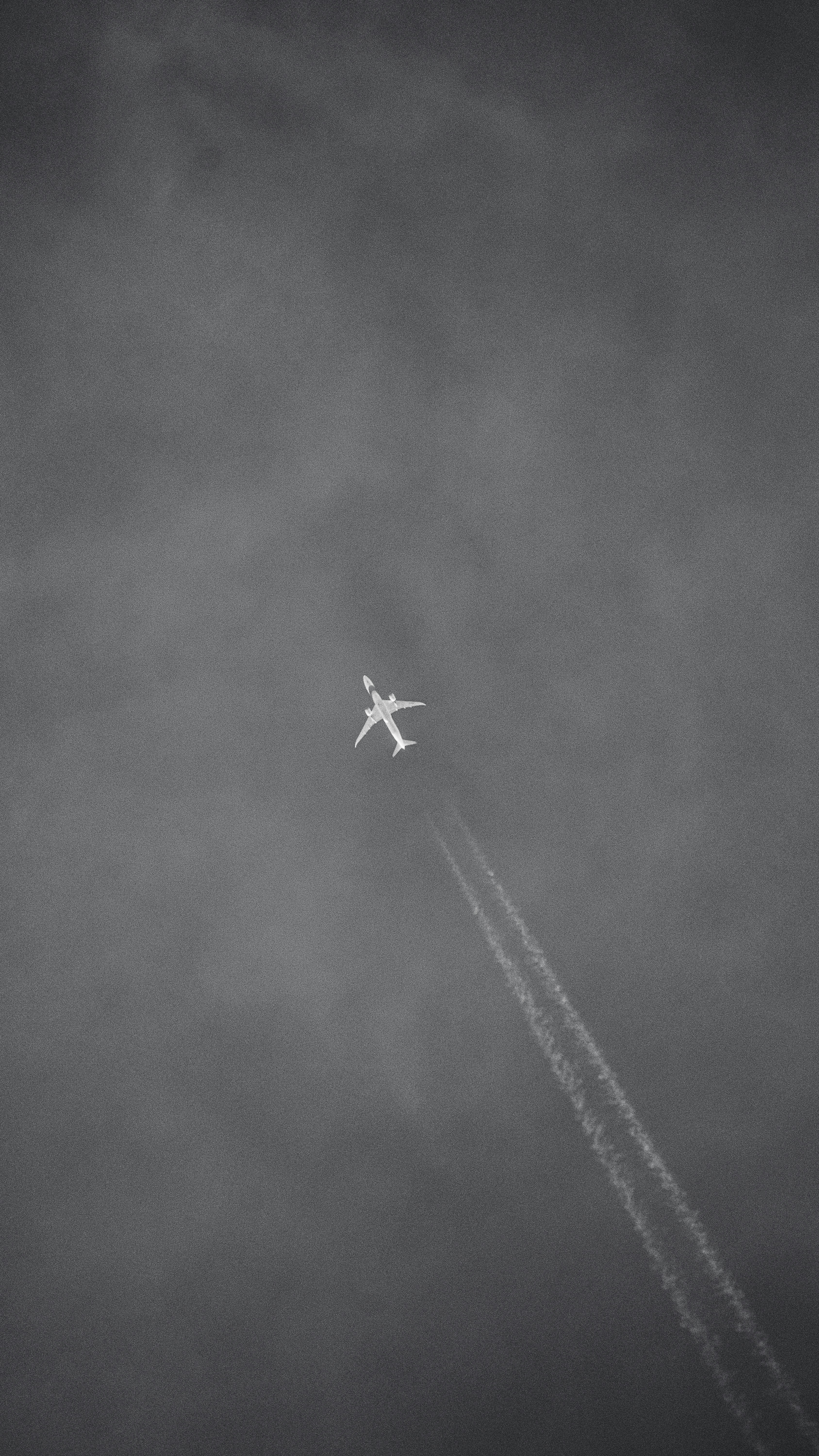 Jetstream Silhouette: A lone aircraft etches contrails through a clouded sky