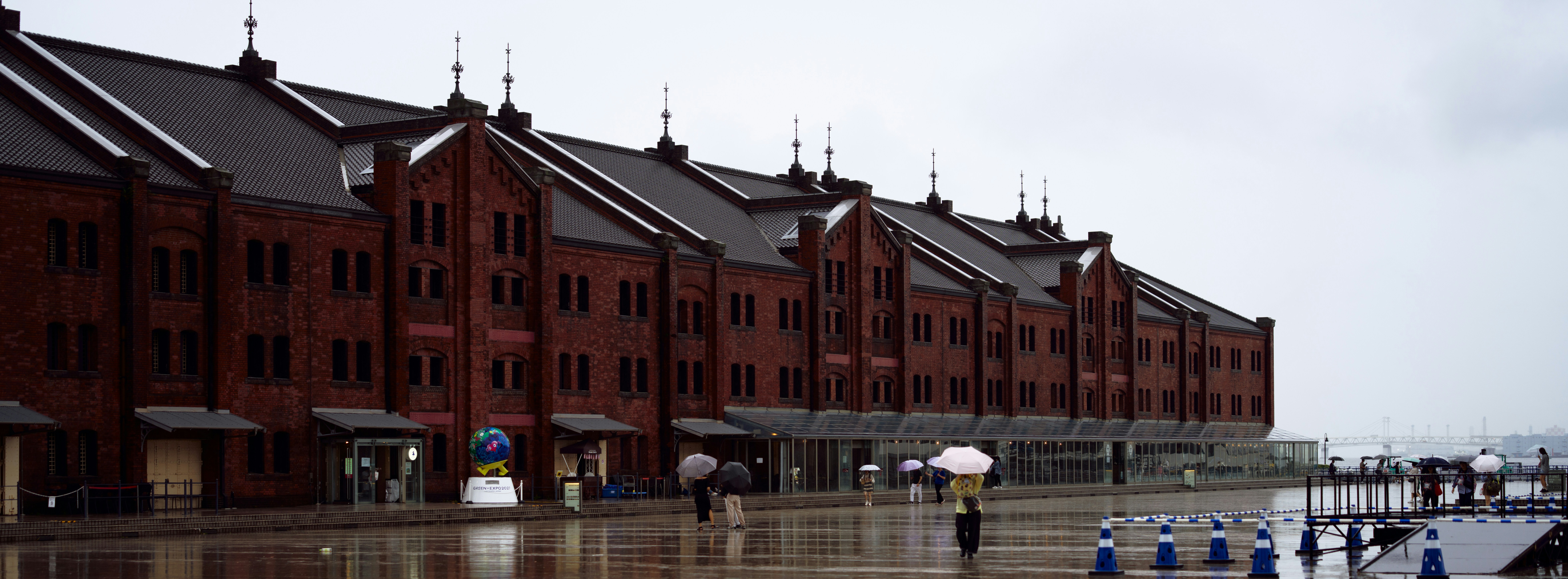 Industrial seaside promenade: red brick warehouses along a rain-soaked quay