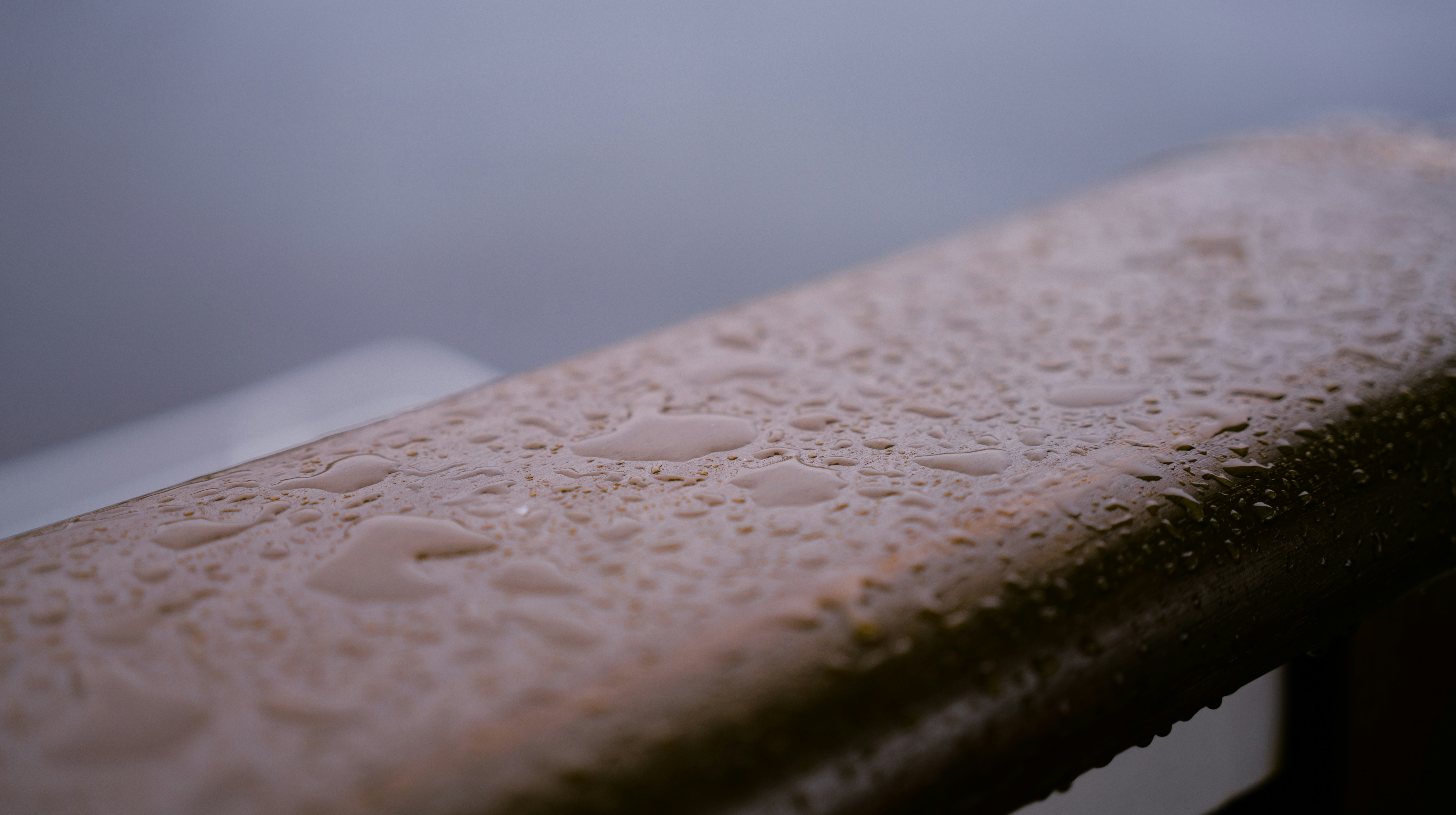 Rain-kissed railing: droplets tracing the edge