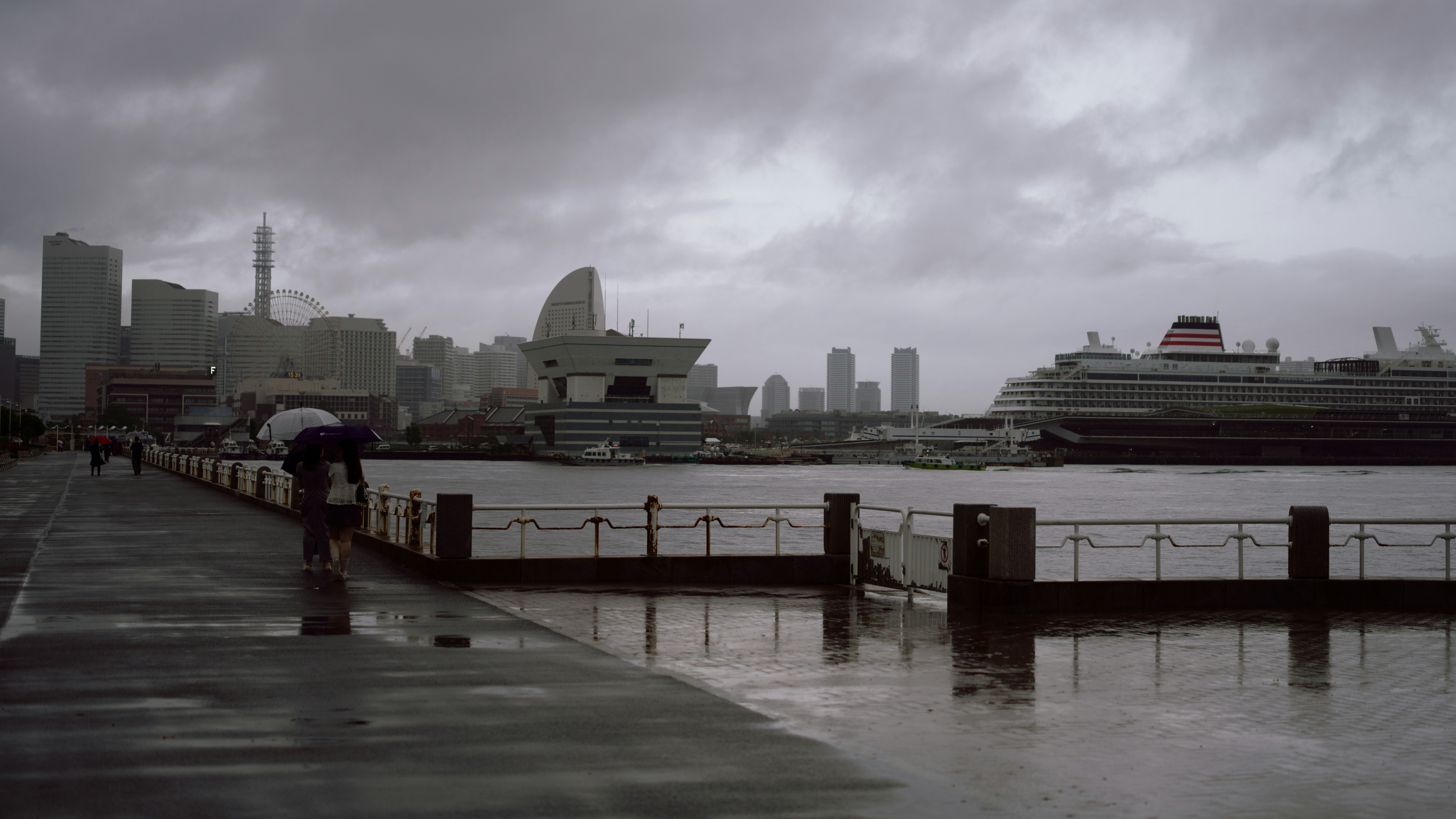 Rainy Thames Walk: Lone Figure Under Umbrella by the Docks