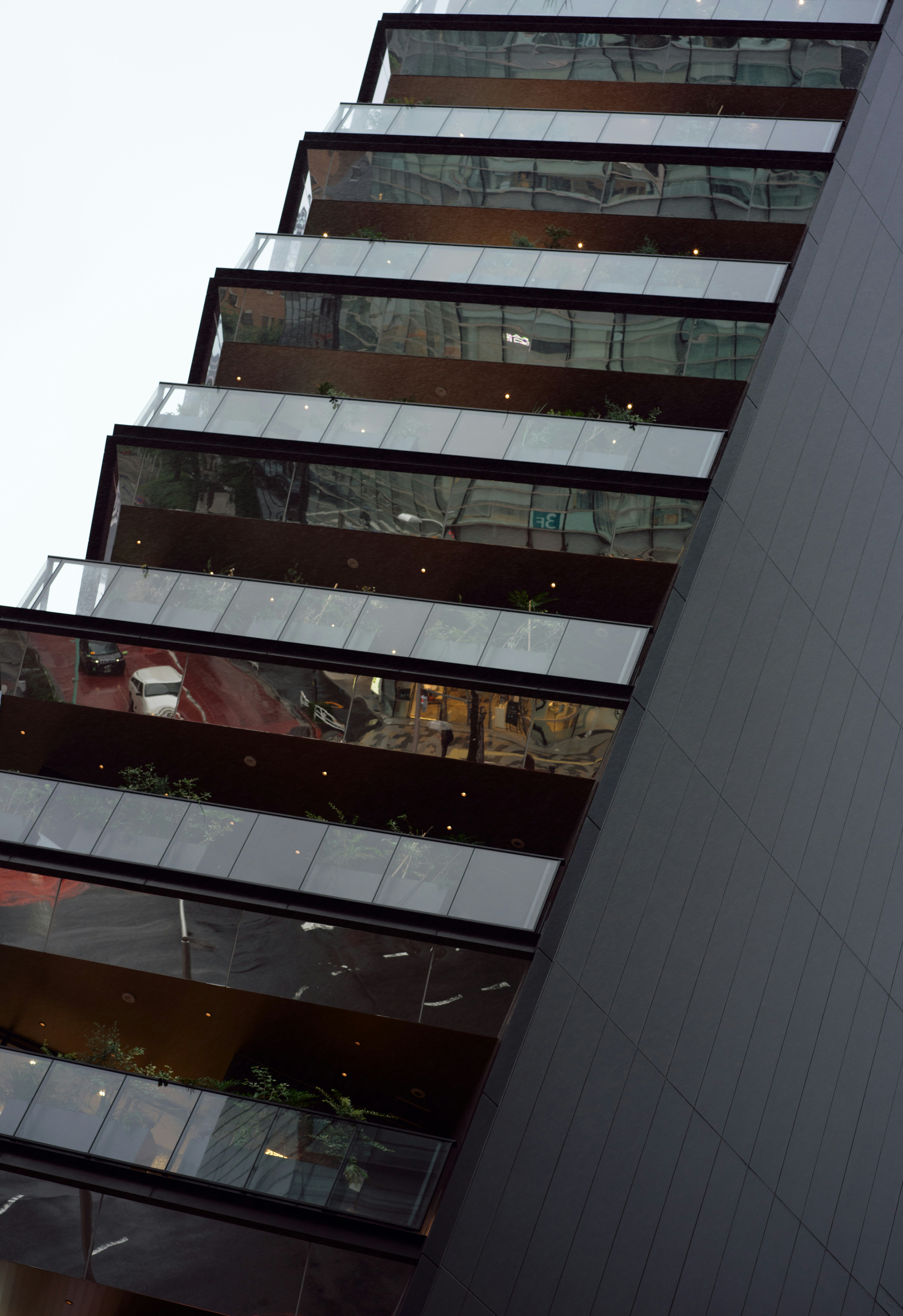 Modern building with stepped glass balconies and plants.