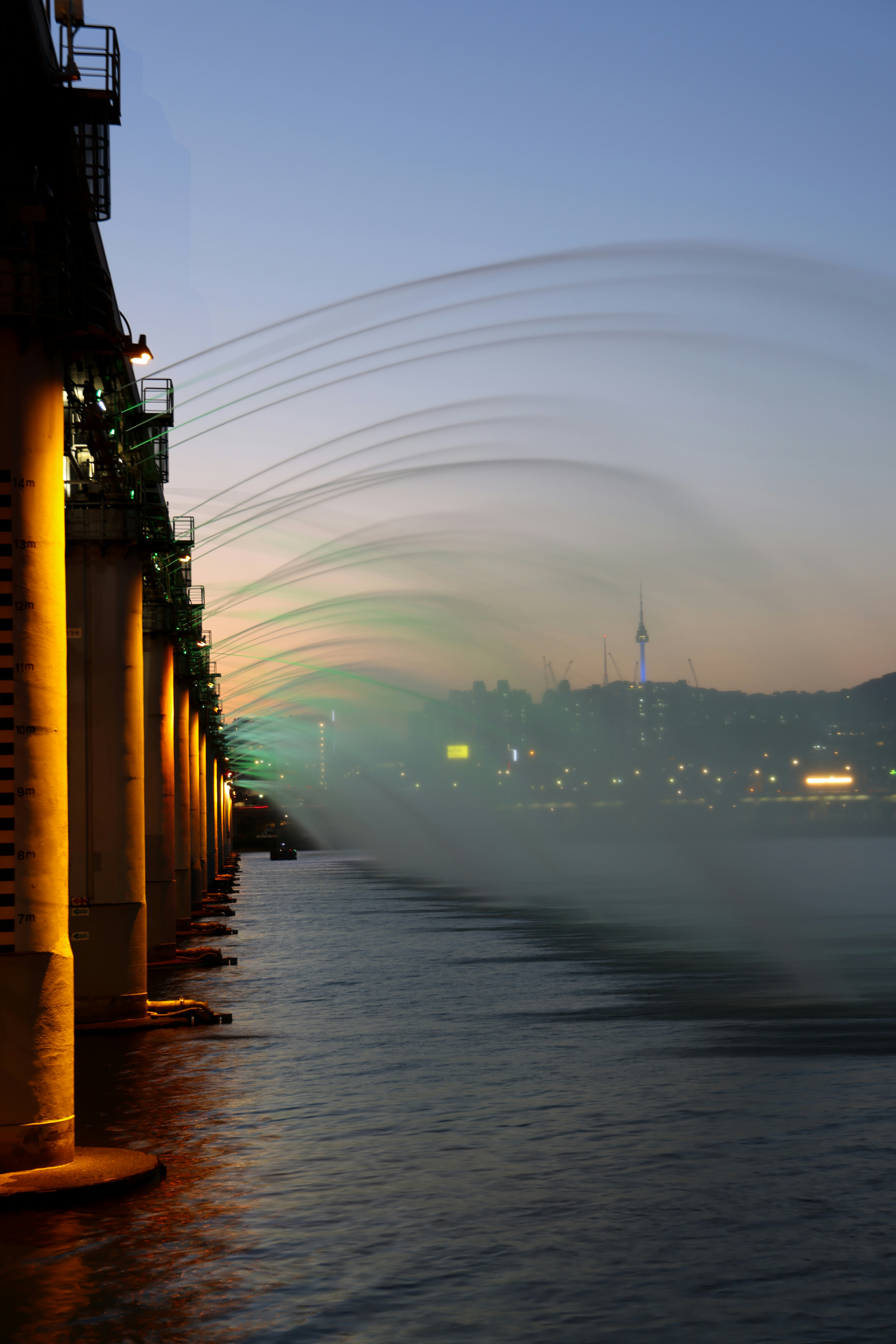 Curved spray over the river: night under the bridge