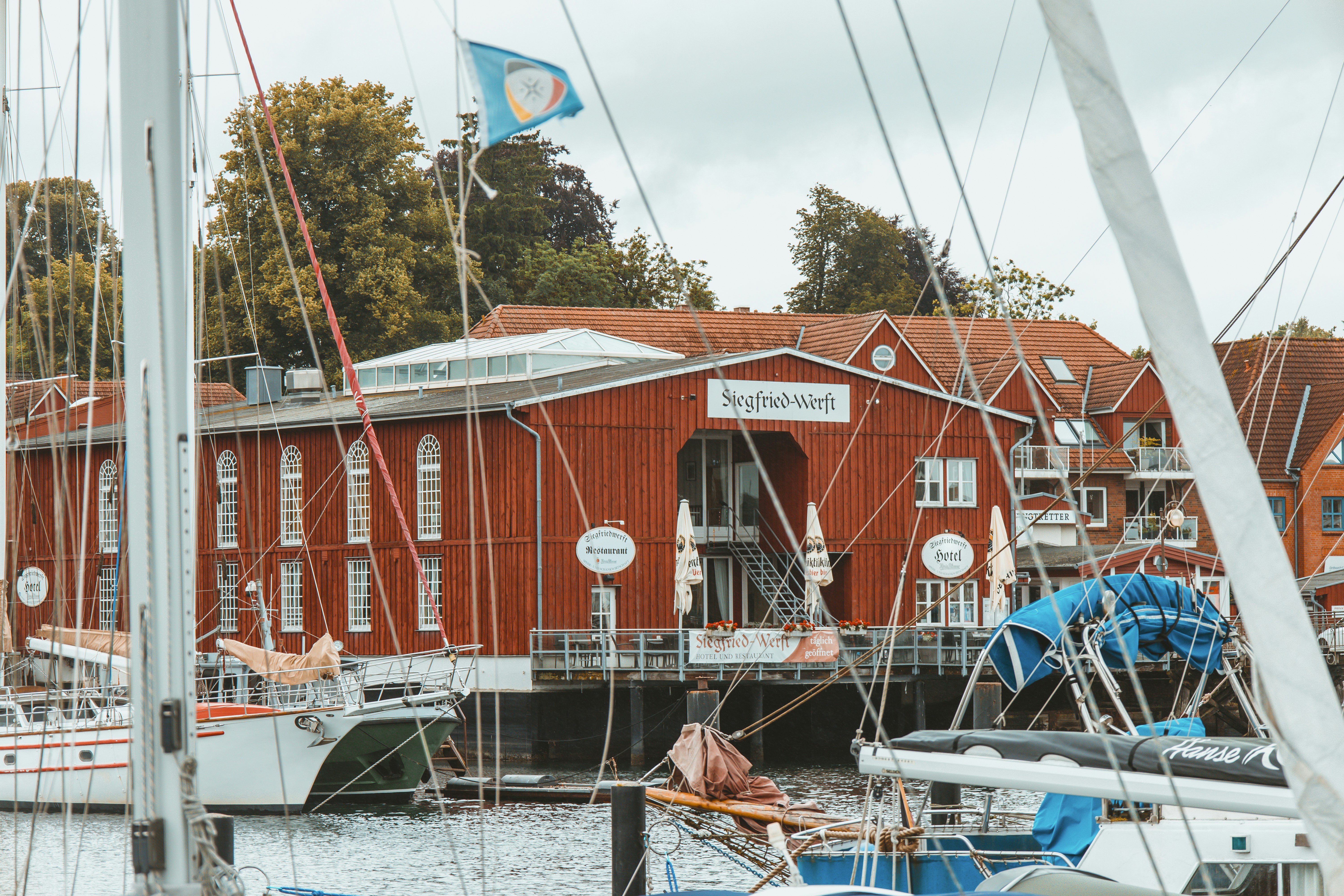Harbor Hub at Dusk: Red Waterfront, Sails, and Docked Boats