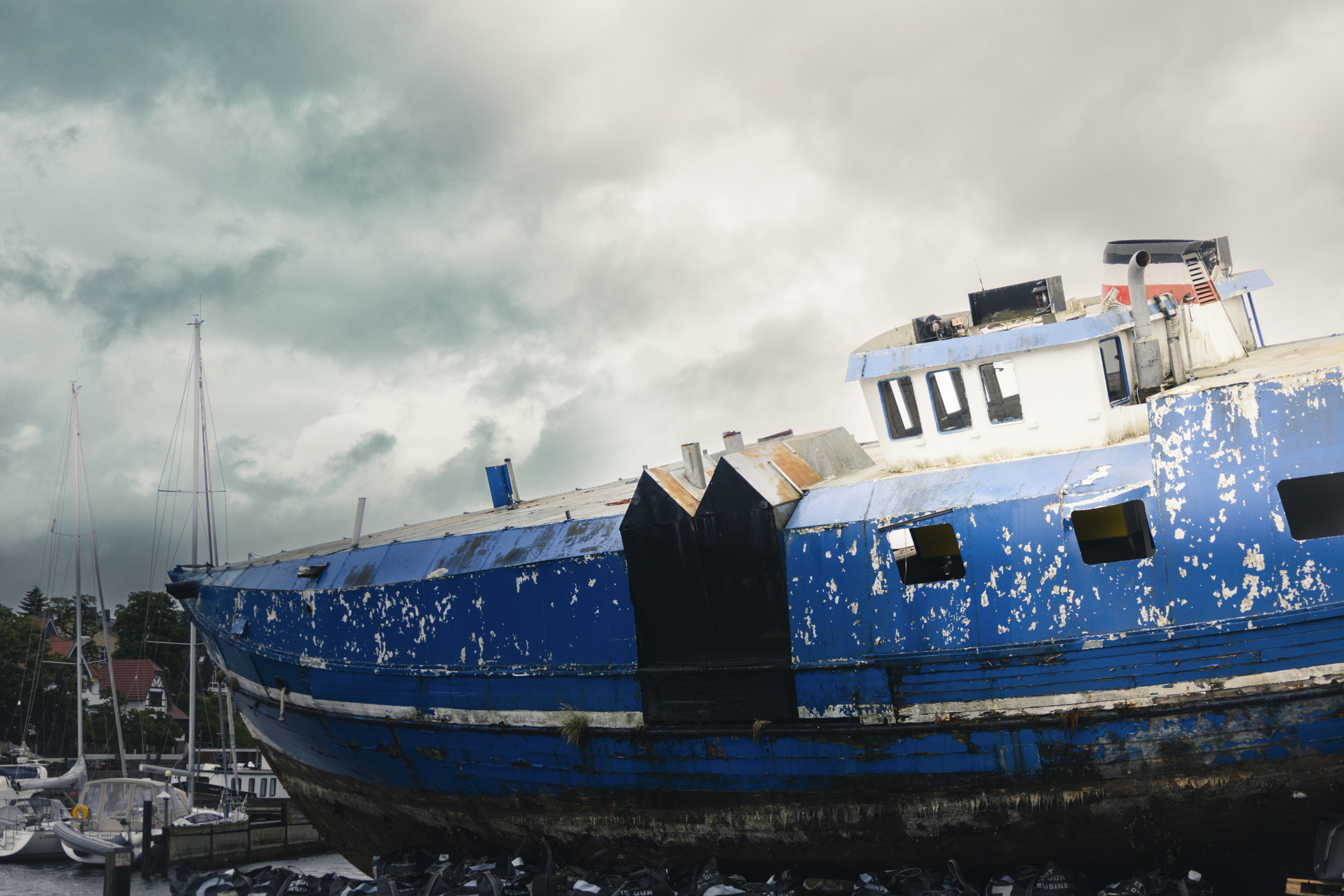 Bleached Blue: A Sunken Vessel Resting Among Quiet Docks