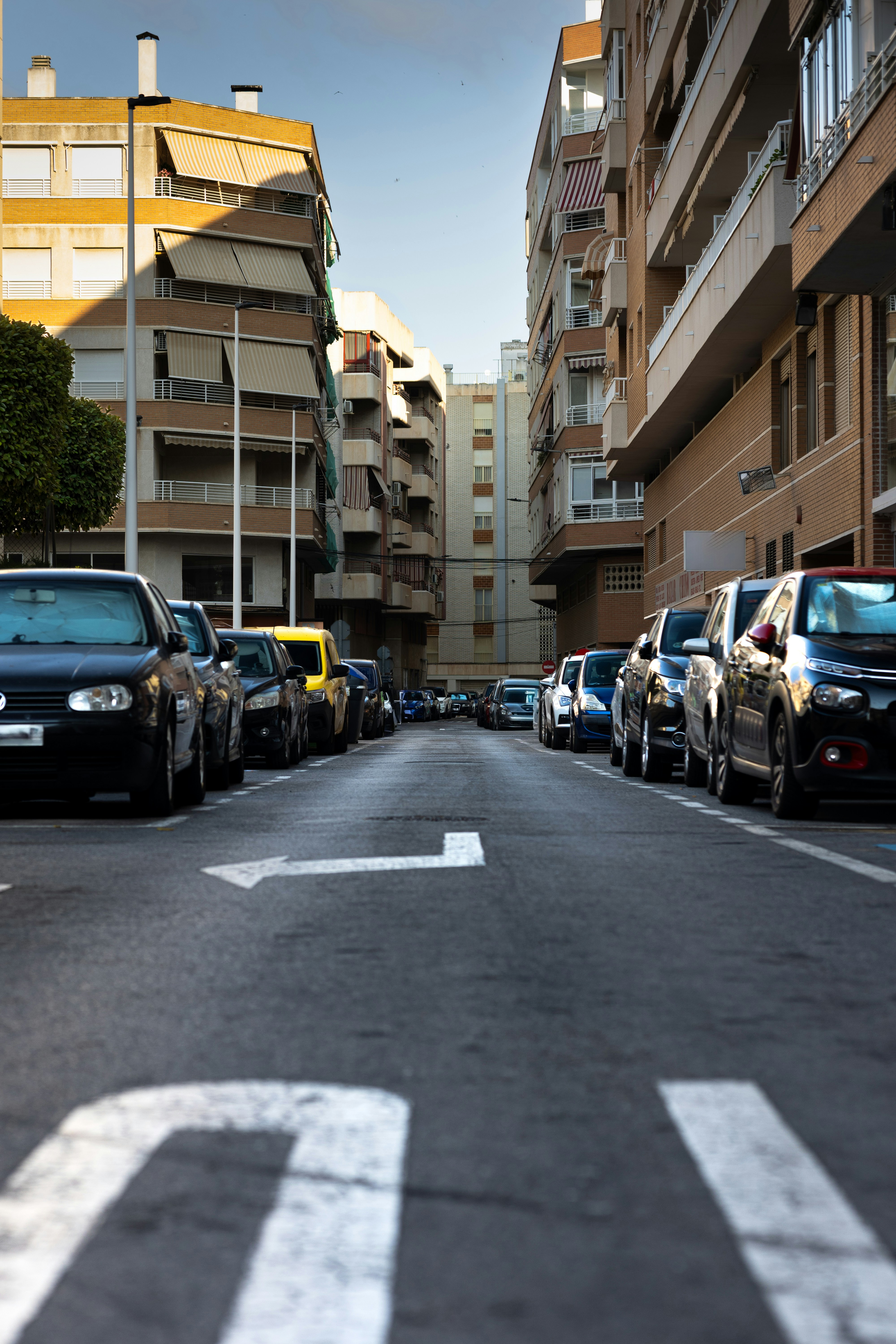 Urban Corridor: Cars Line a Narrow Street Between Living High-Rises
