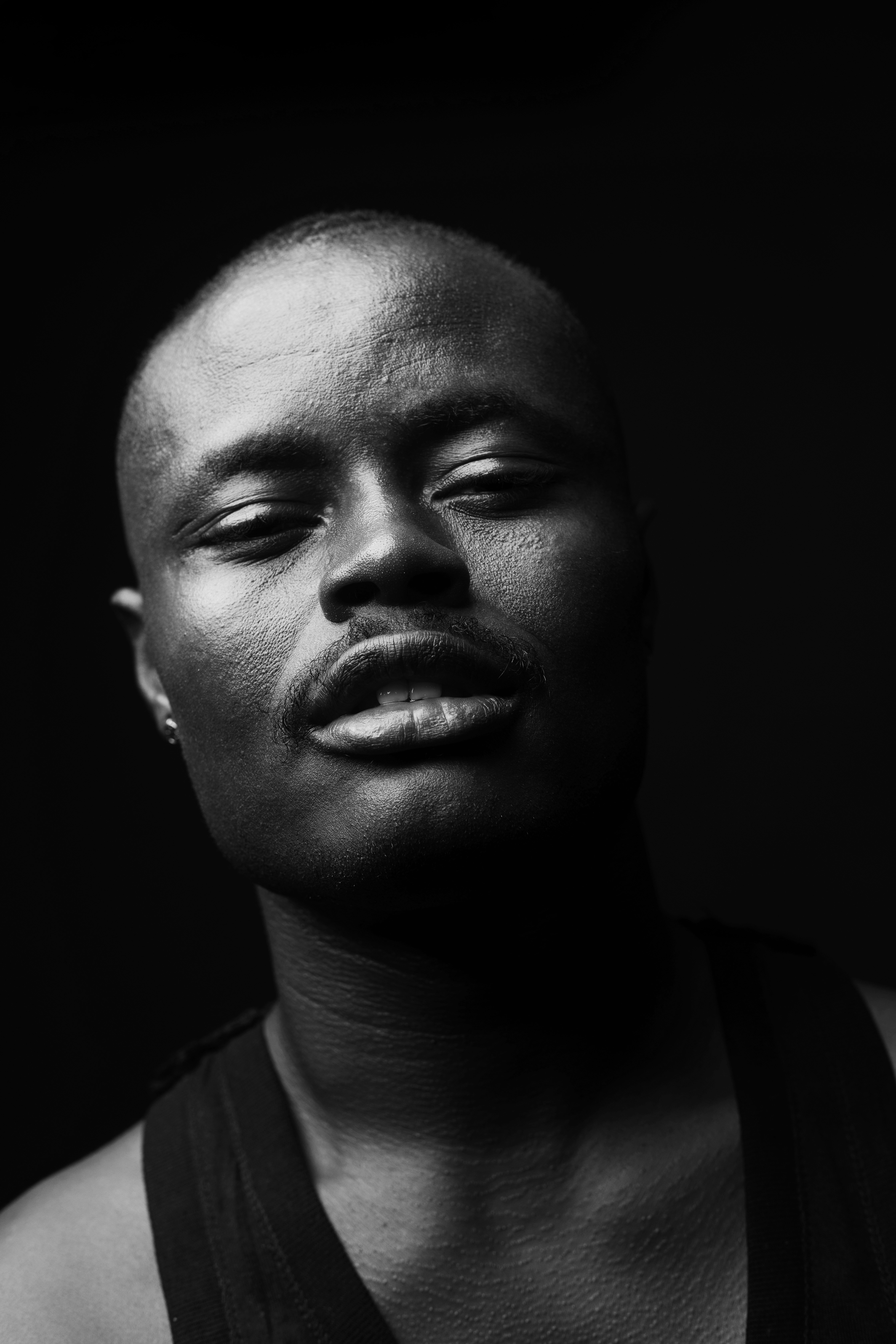Close-up monochrome portrait emphasizing facial contours and texture with dramatic lighting.