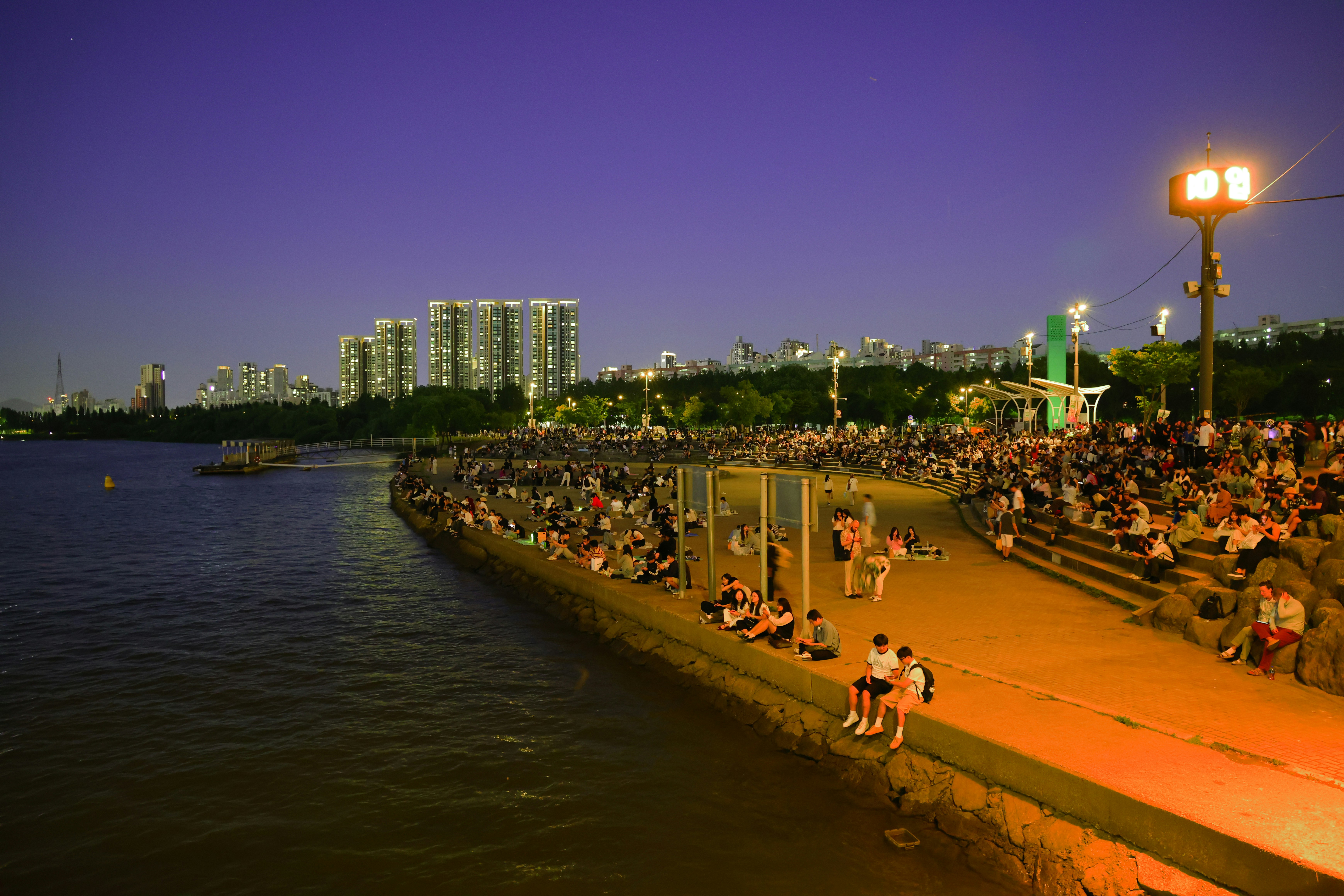 Evening Riverfront Crowd under Gradient Sky