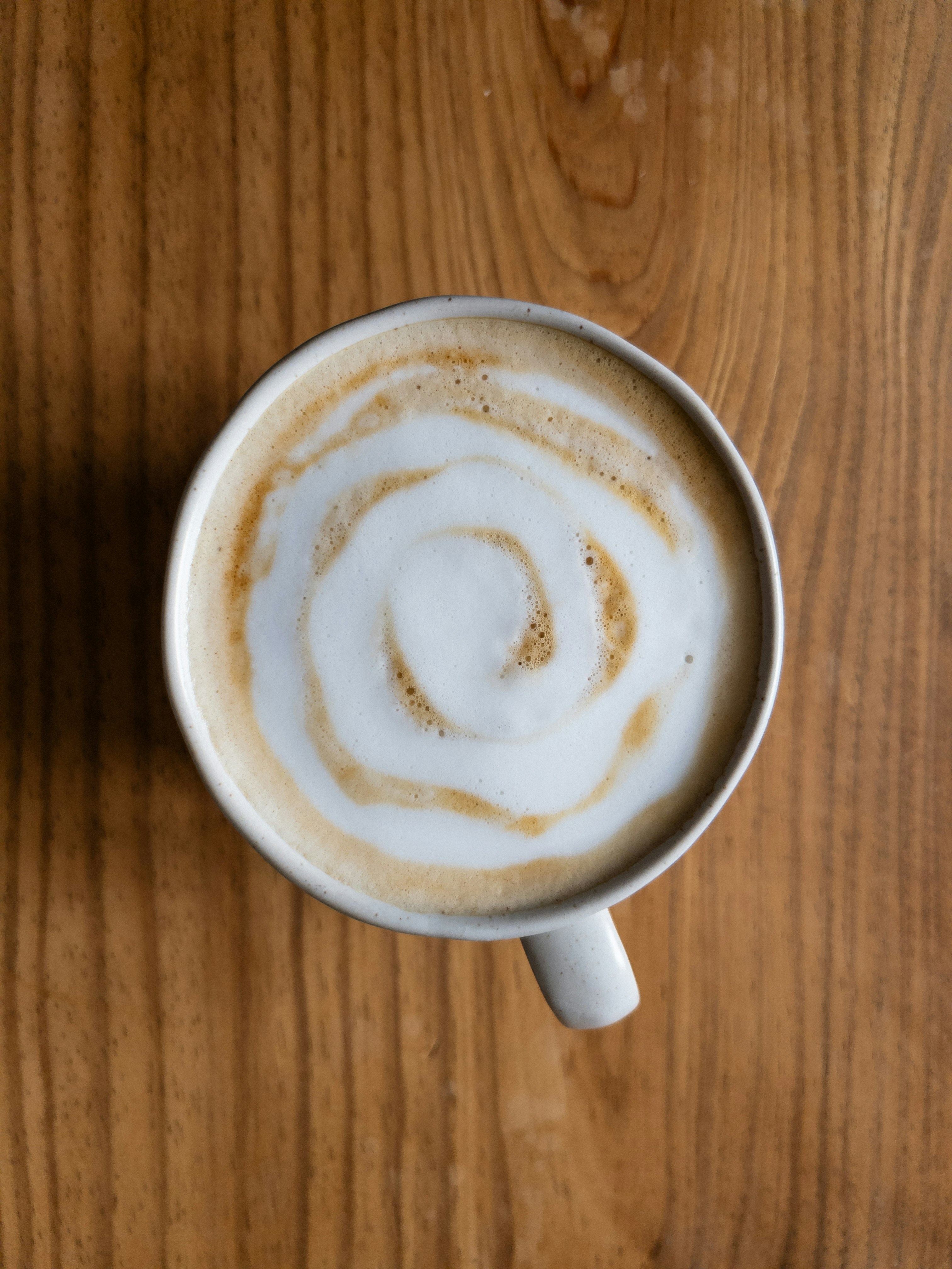 Whirlpool of crema: a latte spiral centered in a wooden cup