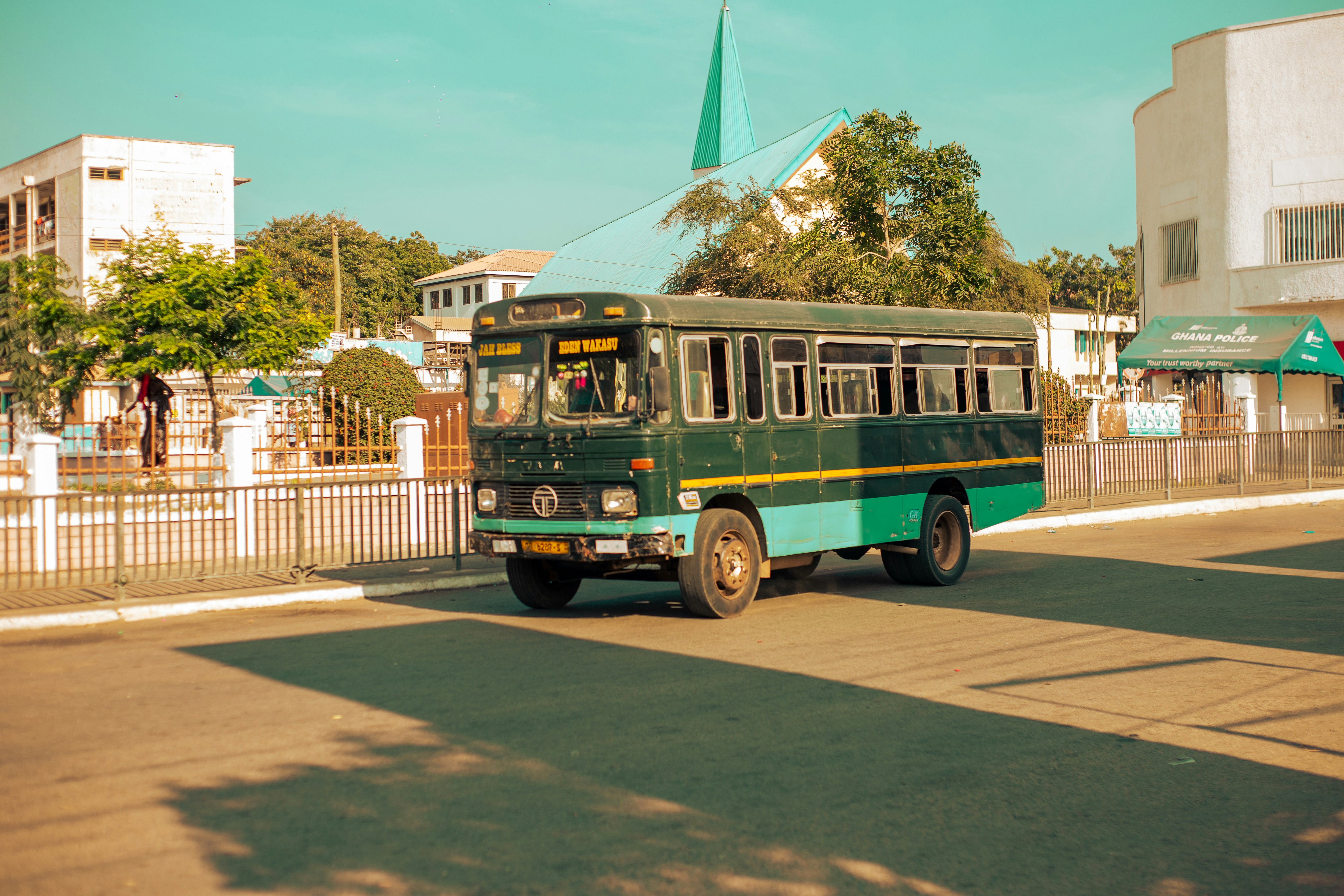  teal bus in a sunlit town square