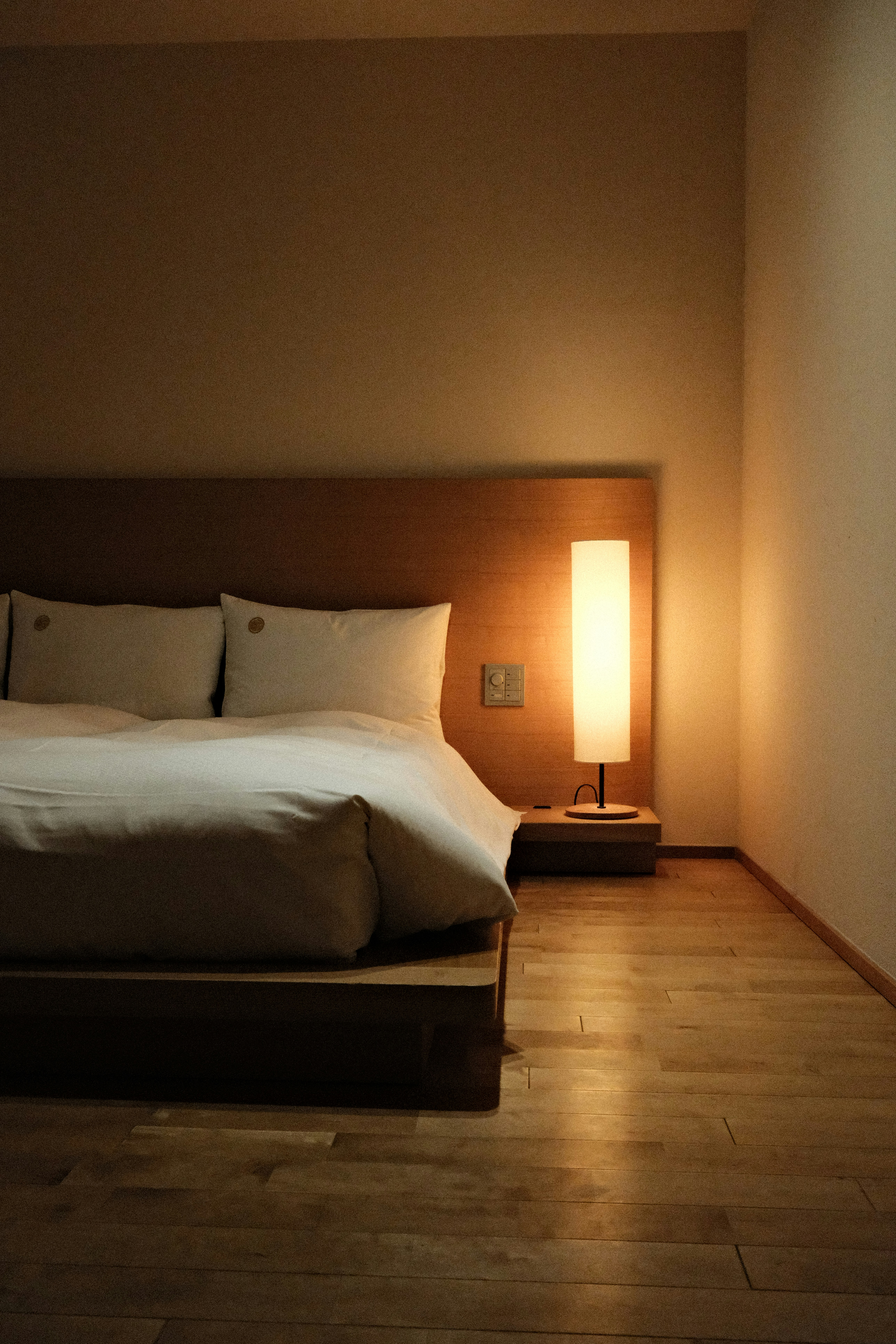 Warm Bedside Glow: Minimalist Hotel Room with Soft Lighting