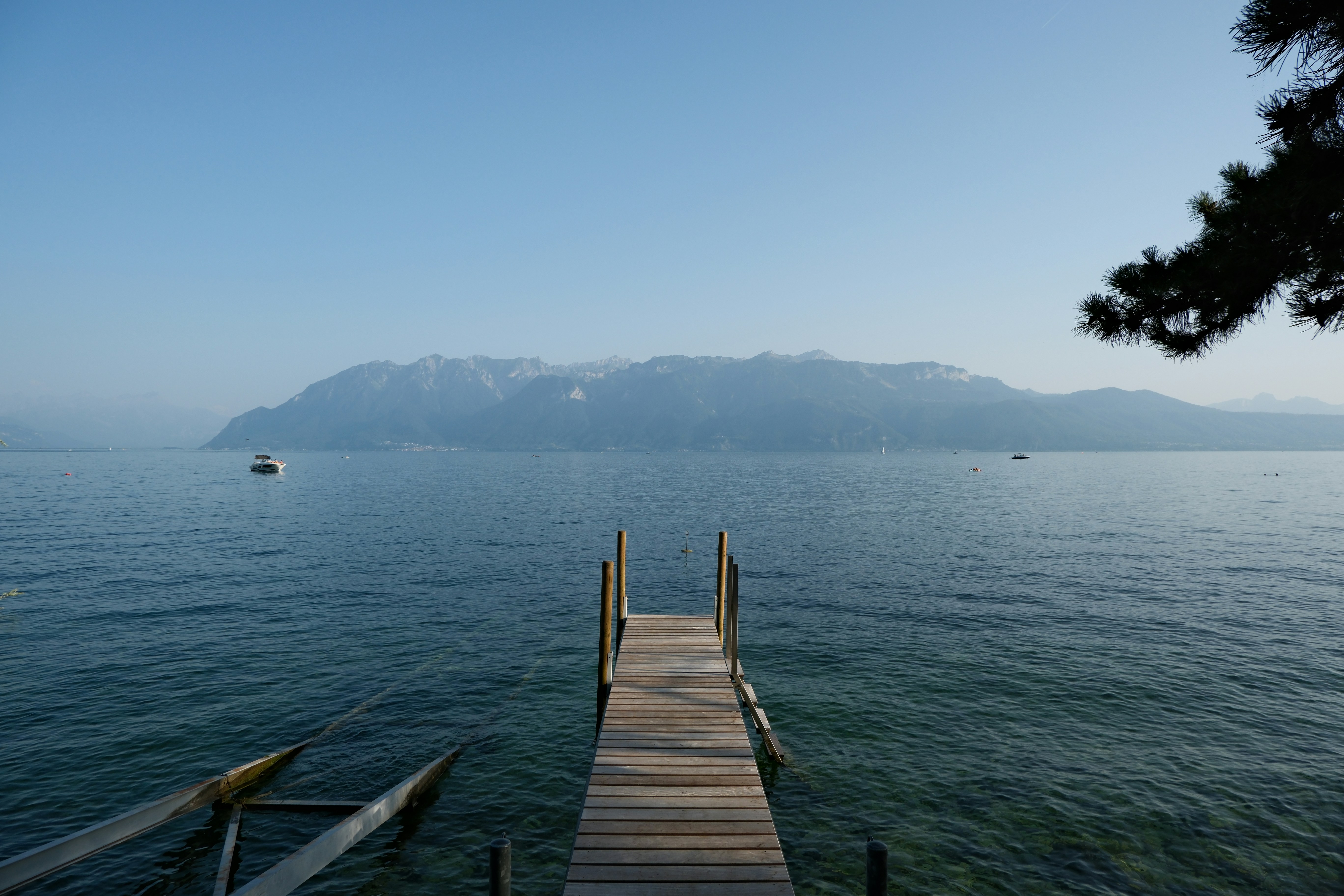 Dock into Calm Blue: A Quiet Pier Reaching Toward Distant Mountains
