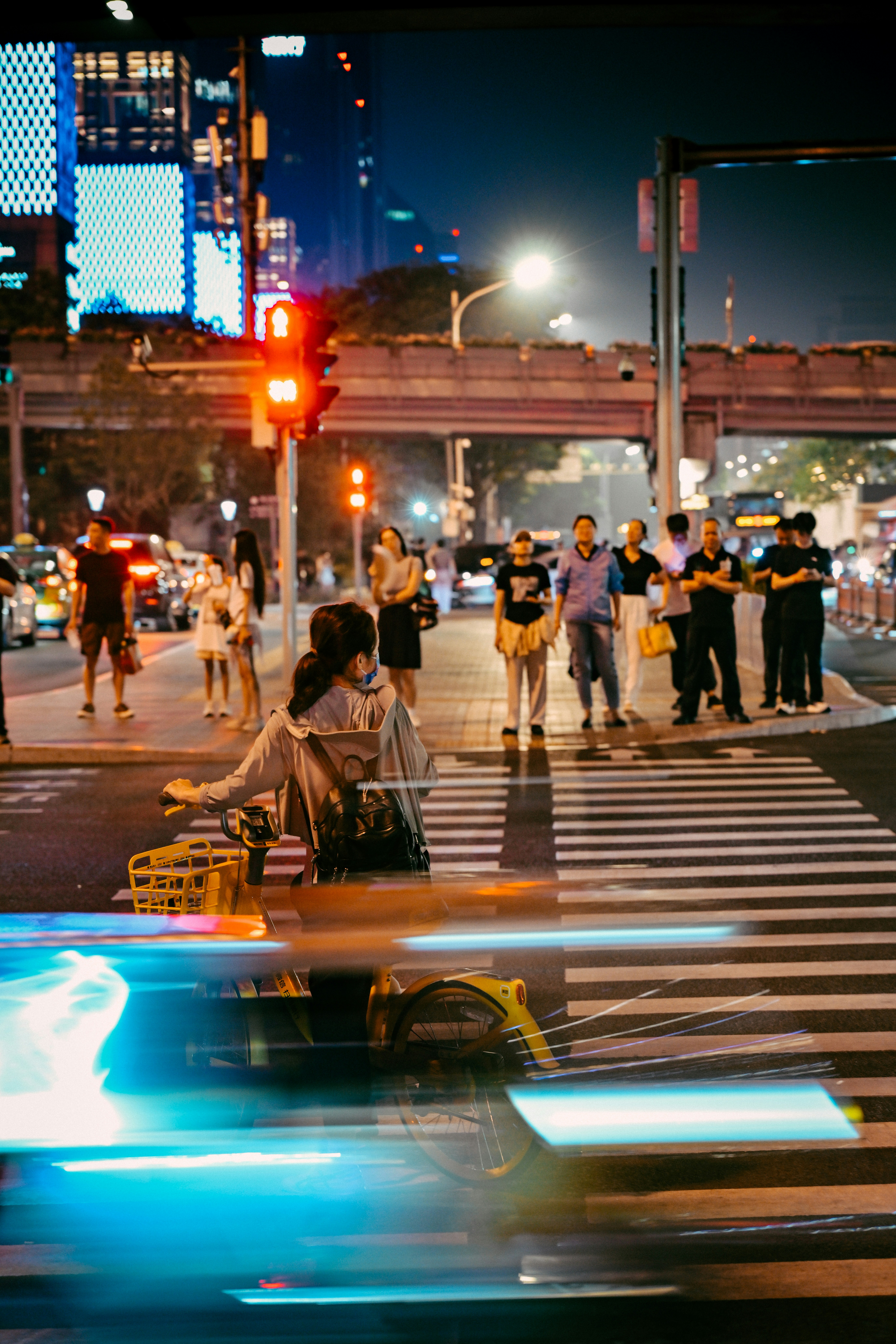Night Crossing: A Rider Pauses at the Neon-Glow Crosswalk