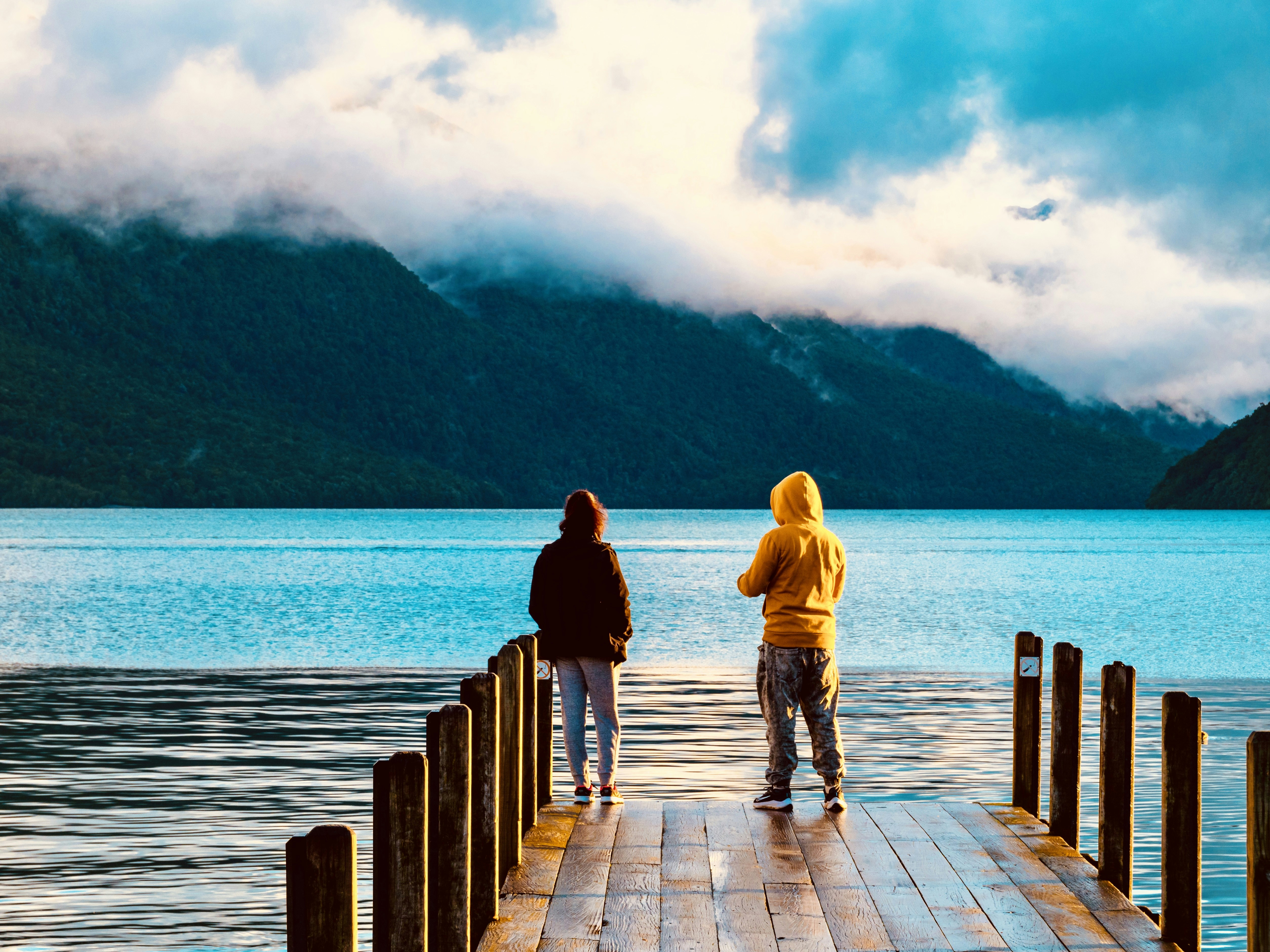 Two Hikers at the End of a Wooden Pier Looking Across a Lake
