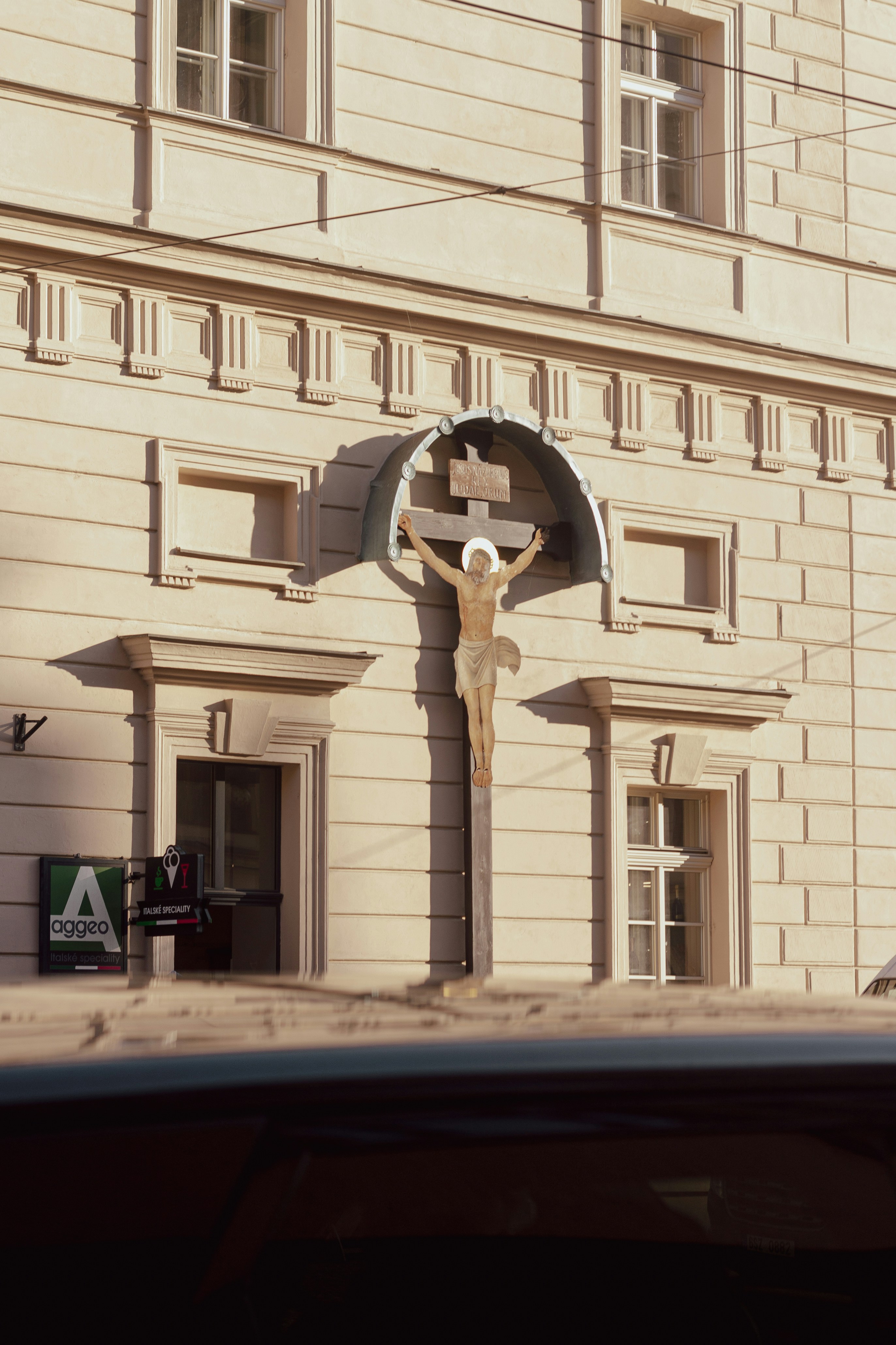Cruciform Insight: A statue framed by a sunlit European facade