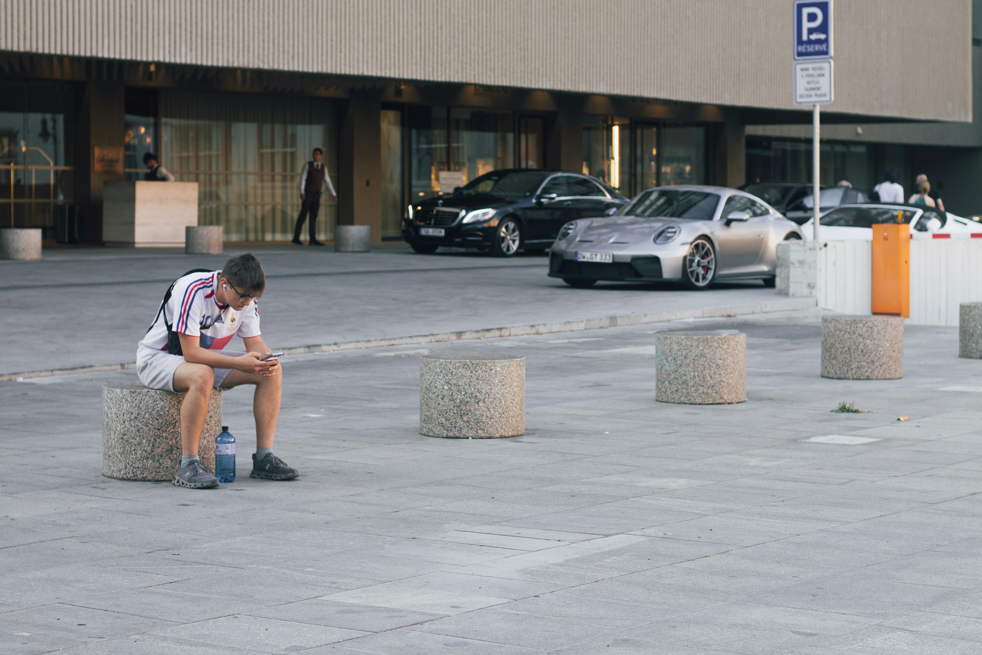 Lonely moment in a paved plaza: a cyclist rests beside concrete stumps