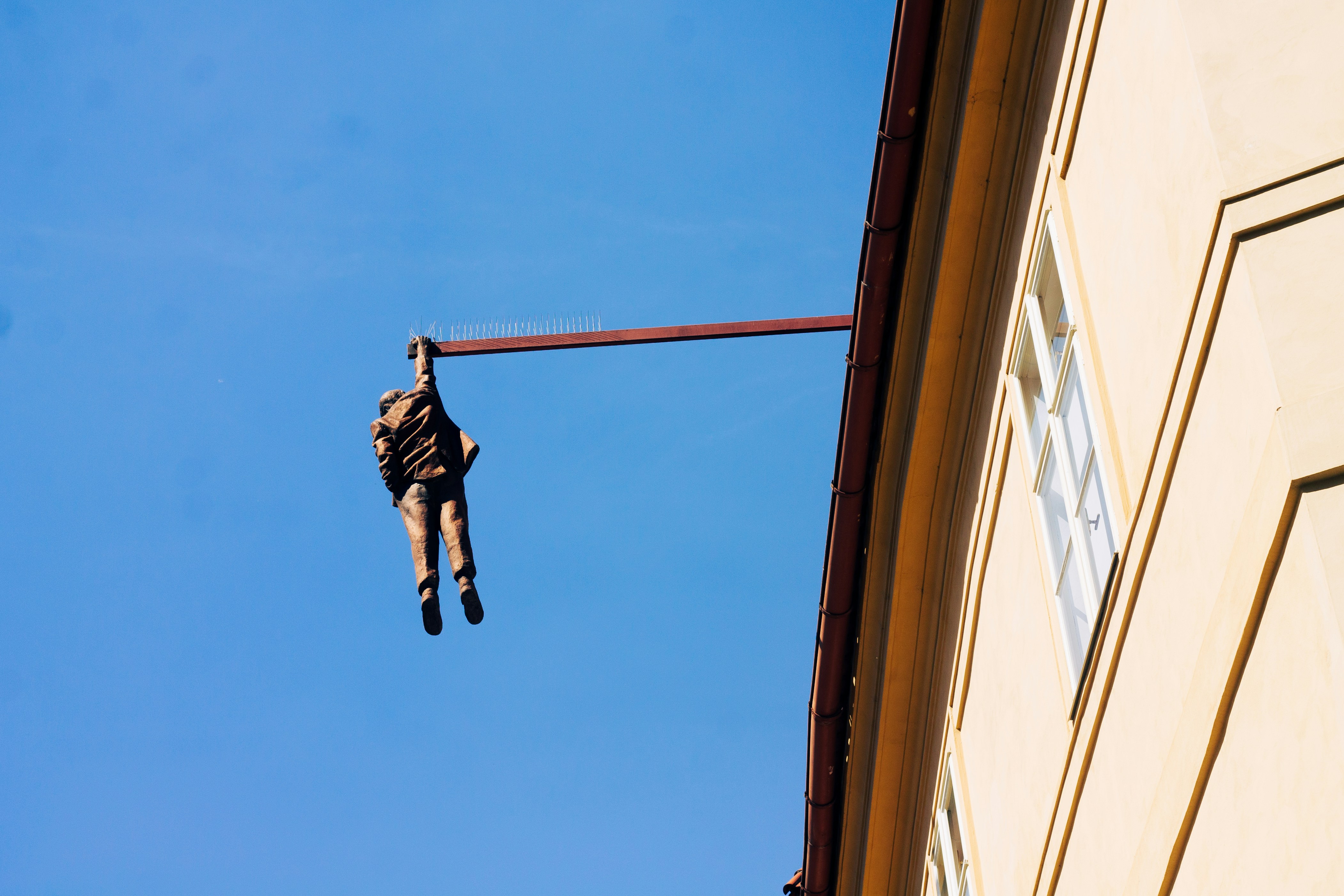 Lone climber in the blue expanse: tethered silhouette against a building edge