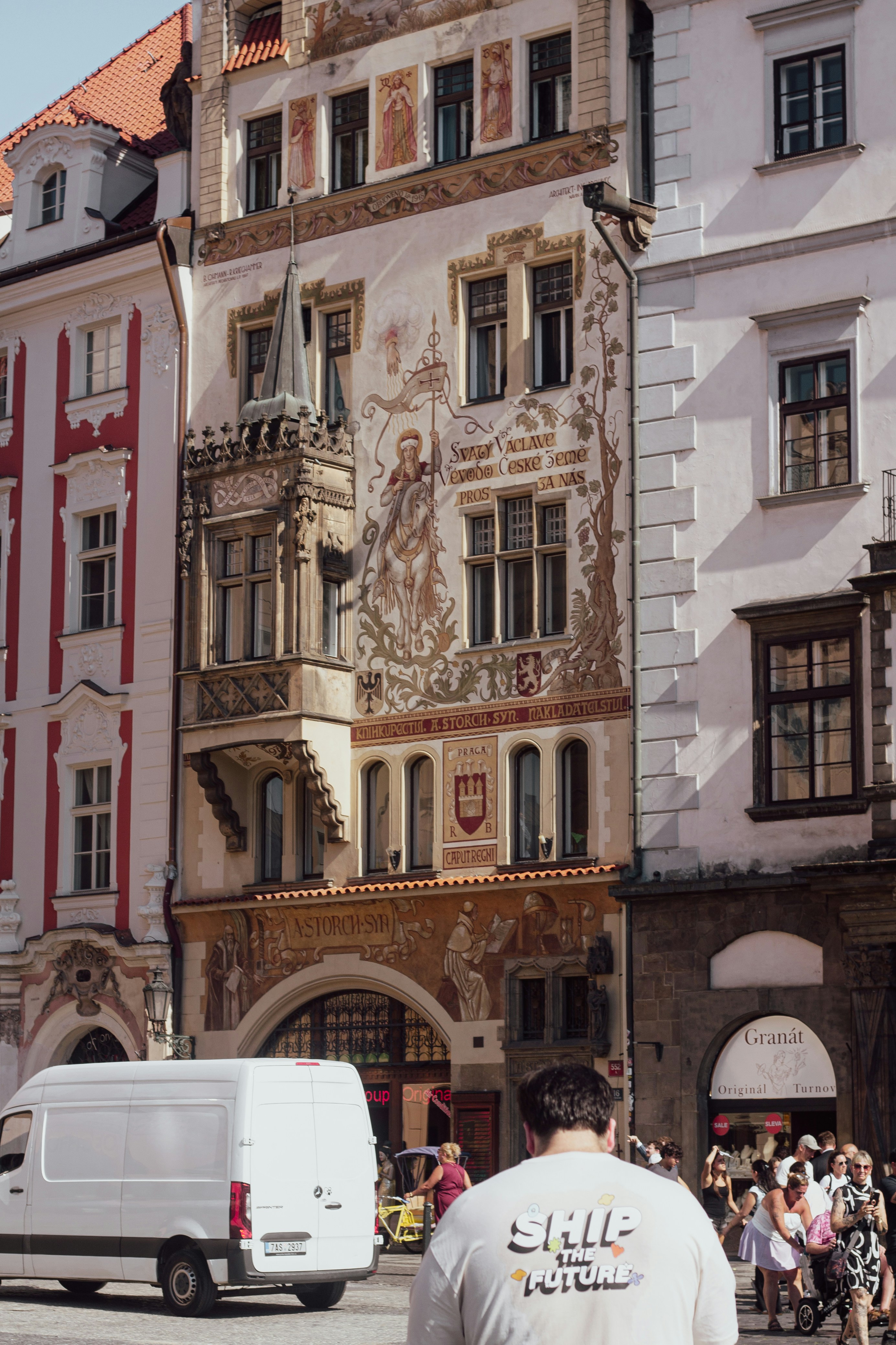 Frescoed Facade of a Historic Clockwork Theater Framed by a Busy Street