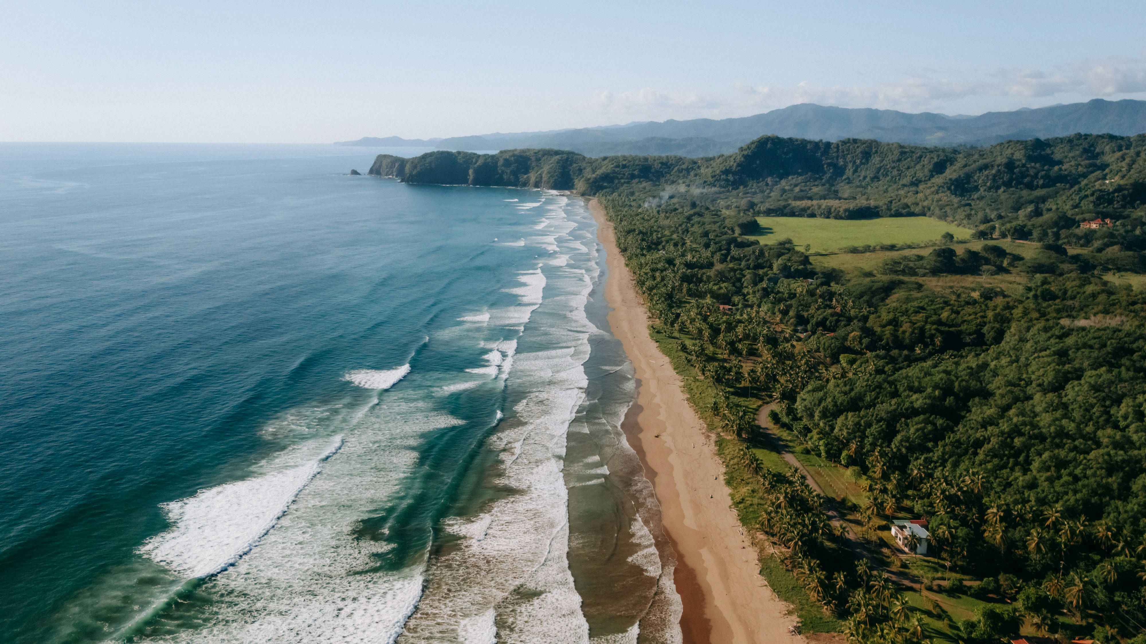 Coastal ribbon: Aerial view of a sunlit shoreline and lush hinterland