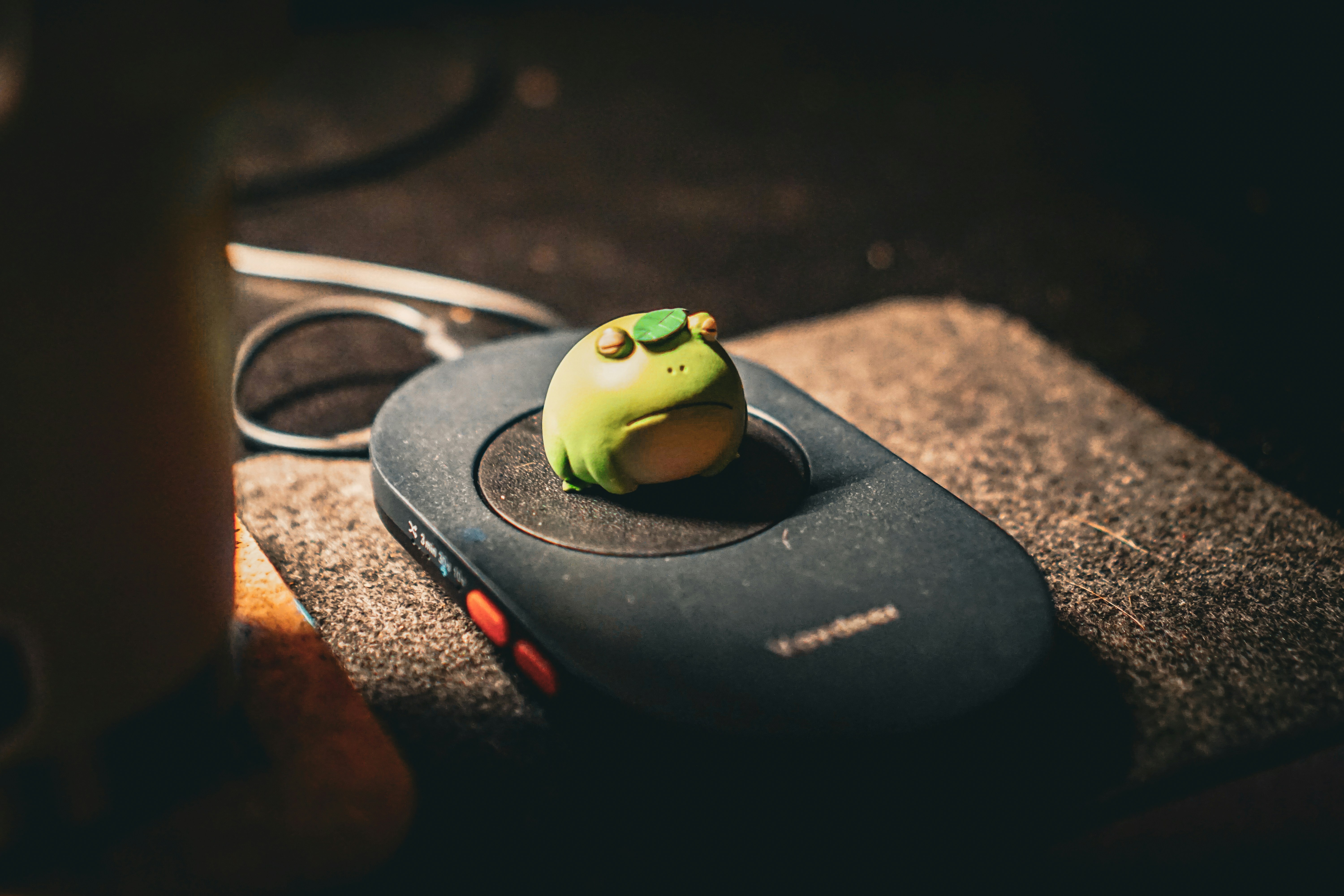 Tiny Frog, Big Moment: A Green Acrobatic Figure on a Mouse Pad