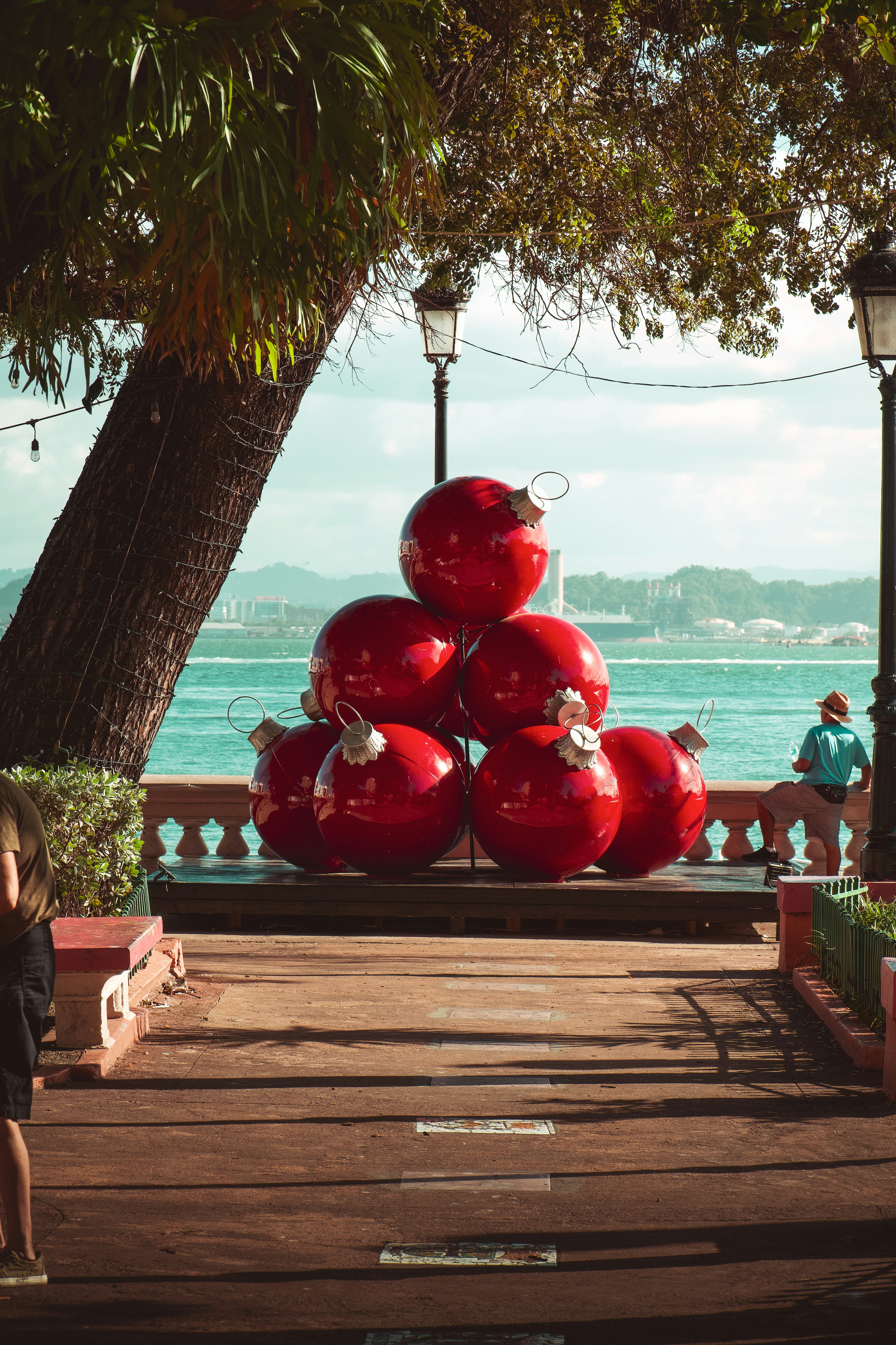 Red Orbs on the Waterfront: A Public Square Sculpture Framed by Trees and Sea