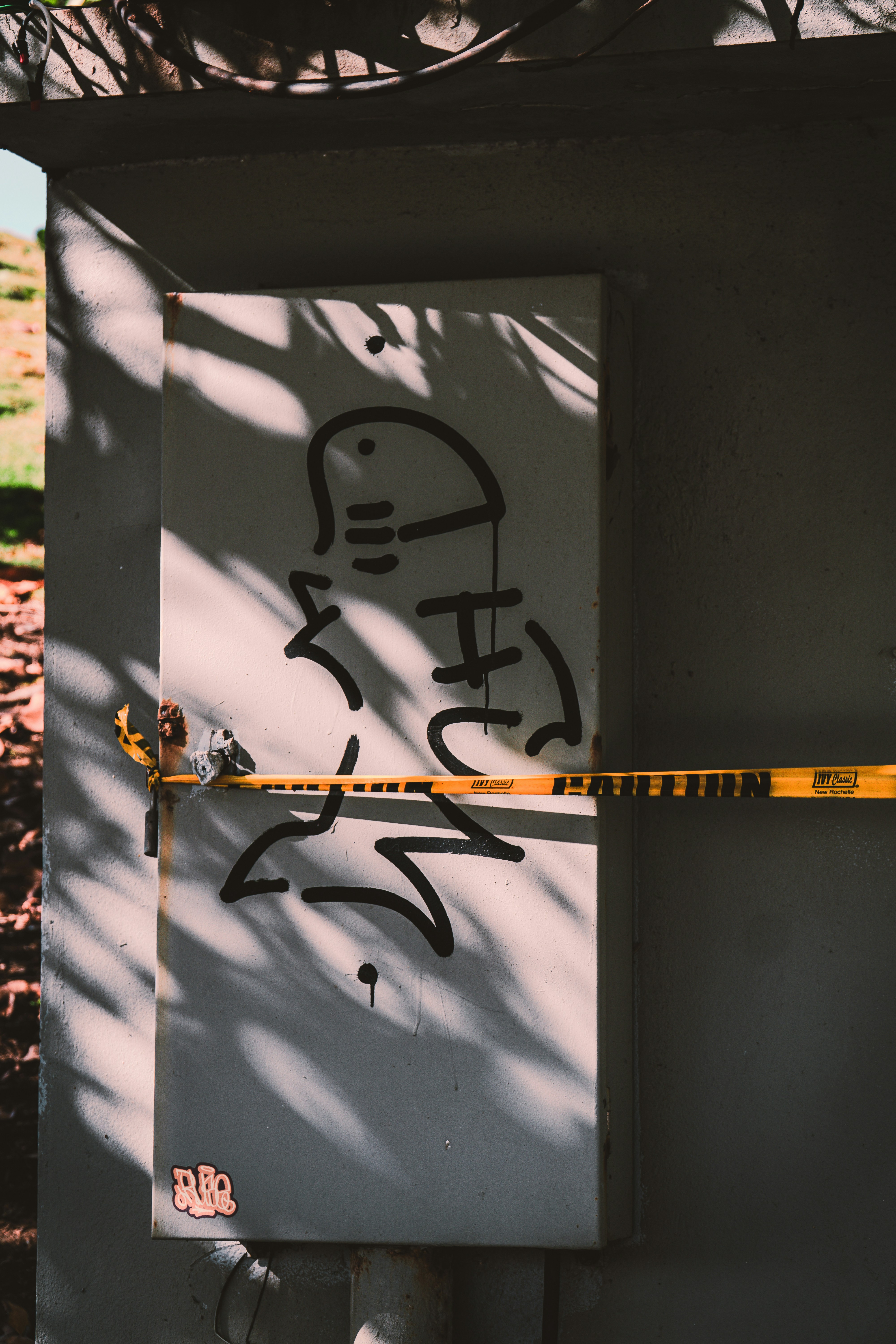 Shadows and Graffiti: A Blocked View Behind Yellow Caution Tape