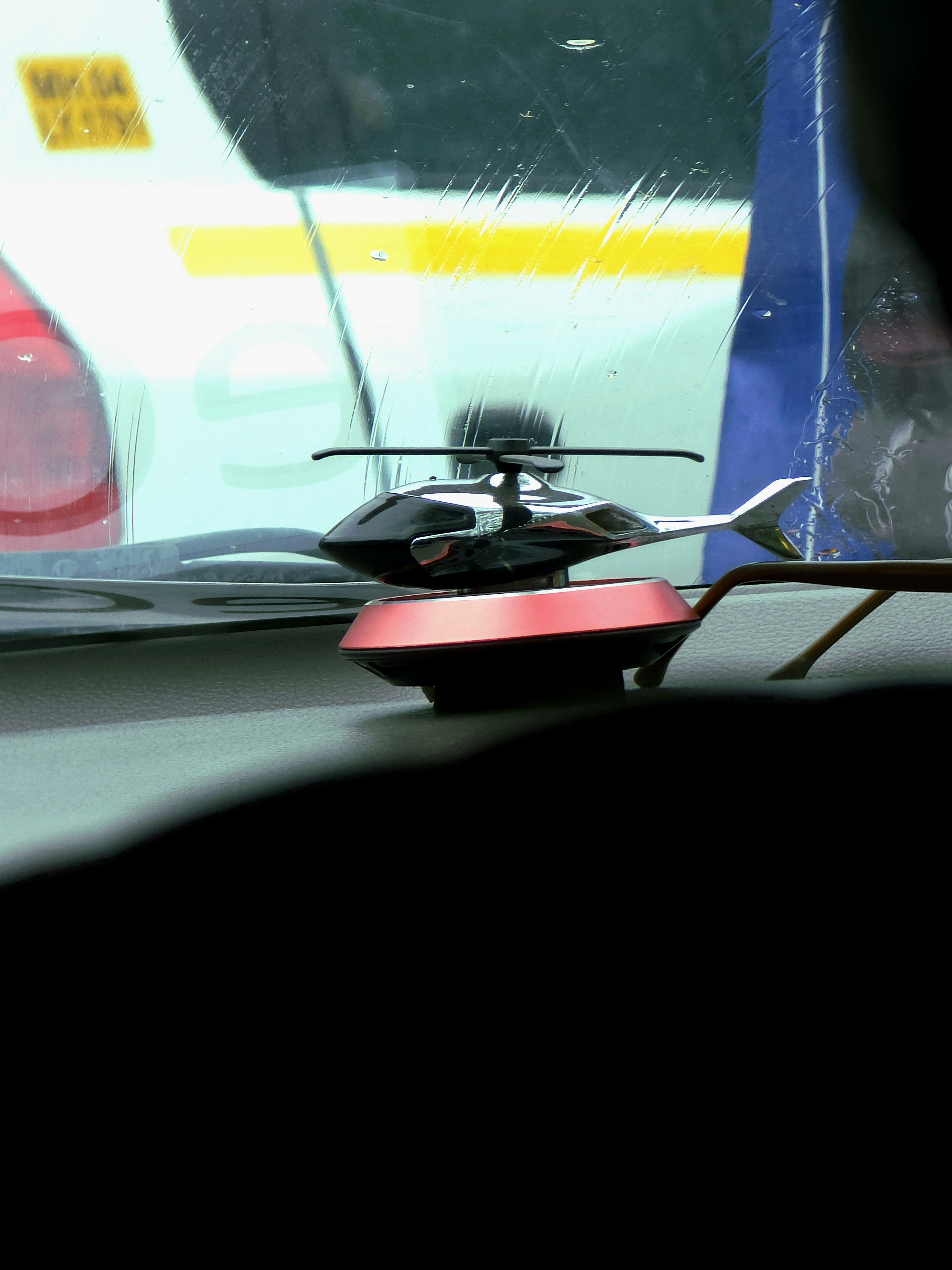 Dashboard Drone: A Miniature Helicopter Rests on the Car Window Windshield