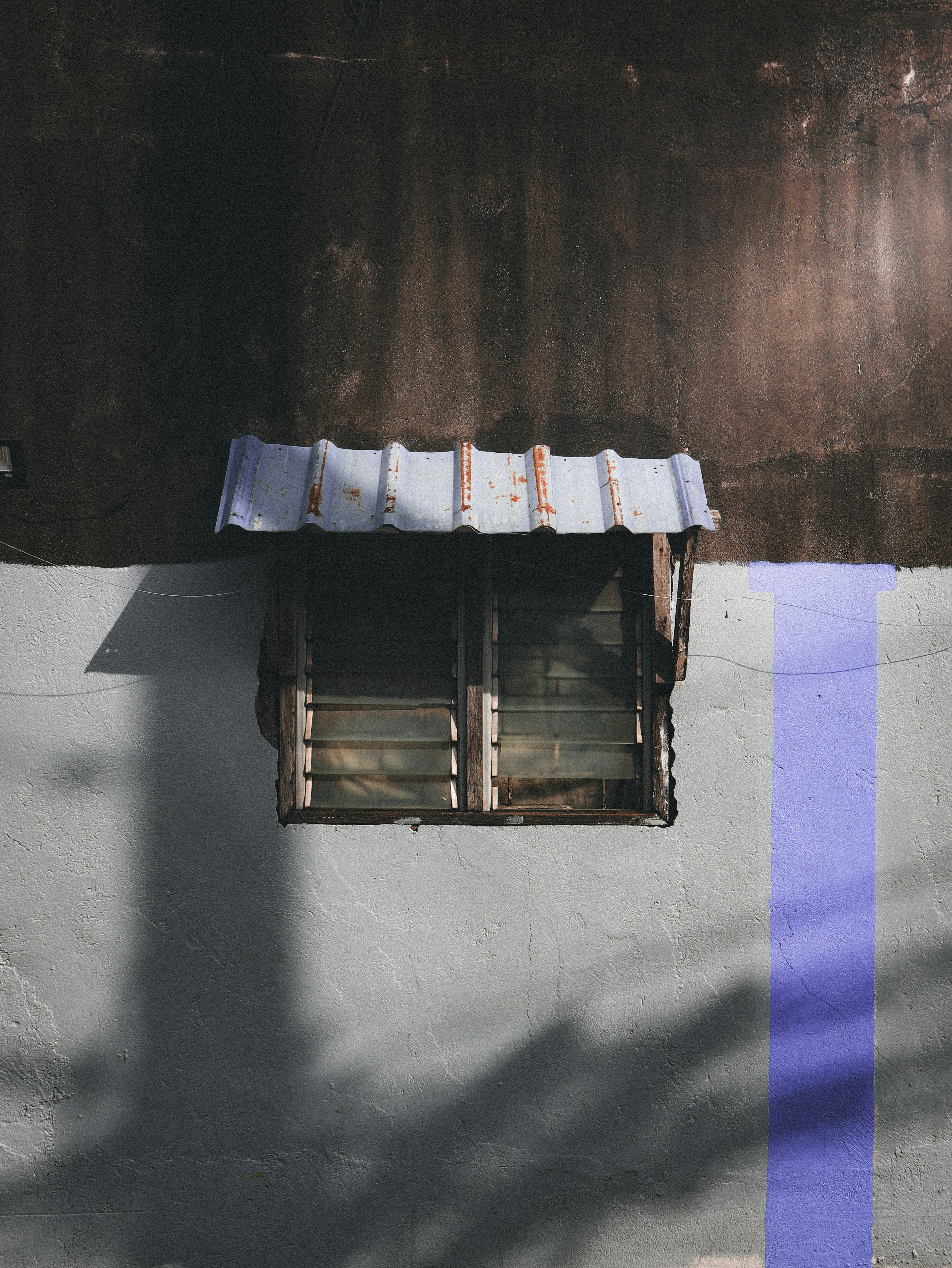 Sunlit Window Lades: A Dormant Facade Under a Worn Tin Roof