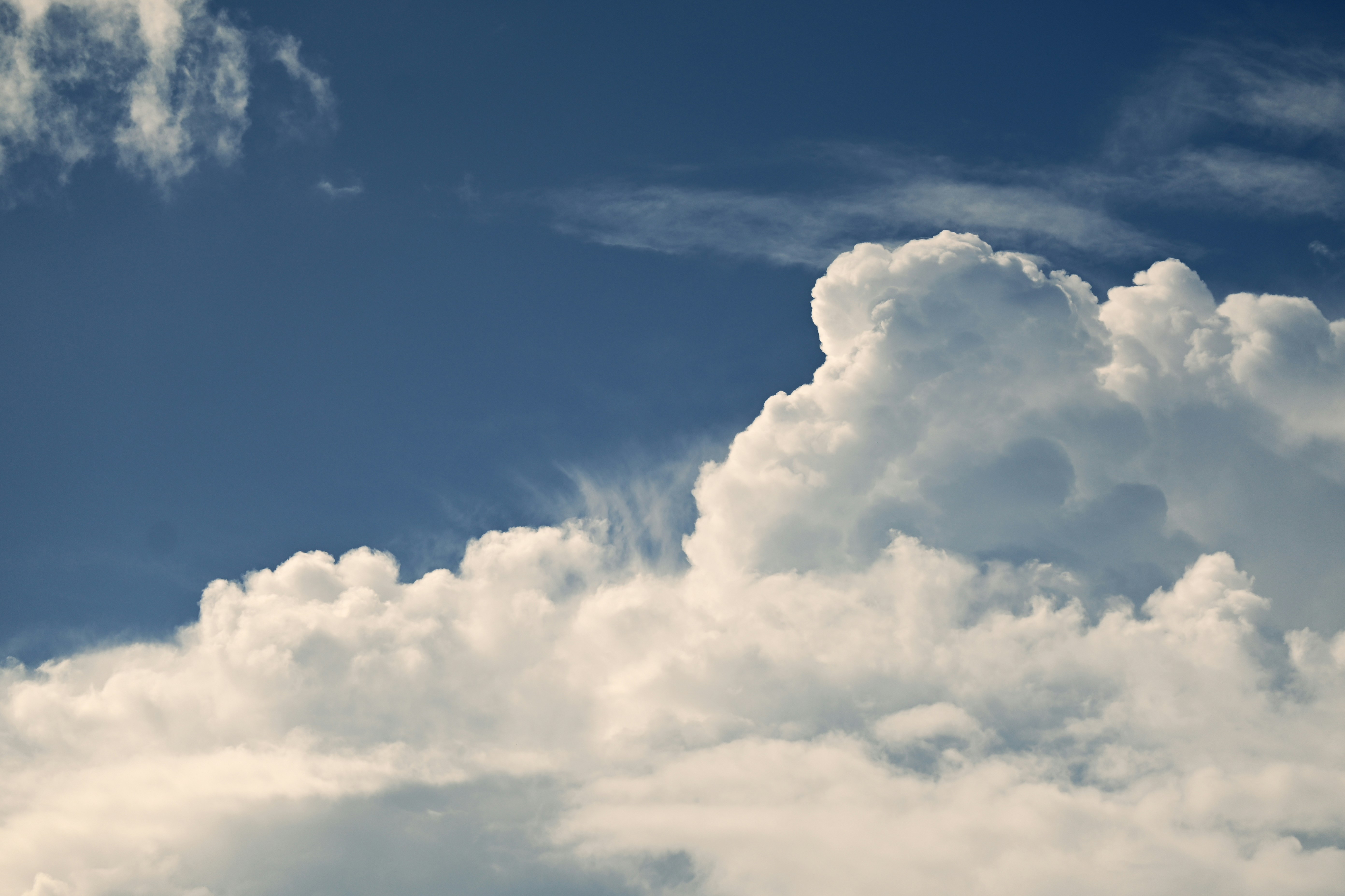 Soft, luminous clouds drift across a clear blue sky, capturing a moment of serene atmospheric depth. This is a natural sky photograph with no foreground subjects, focusing on weather and light.