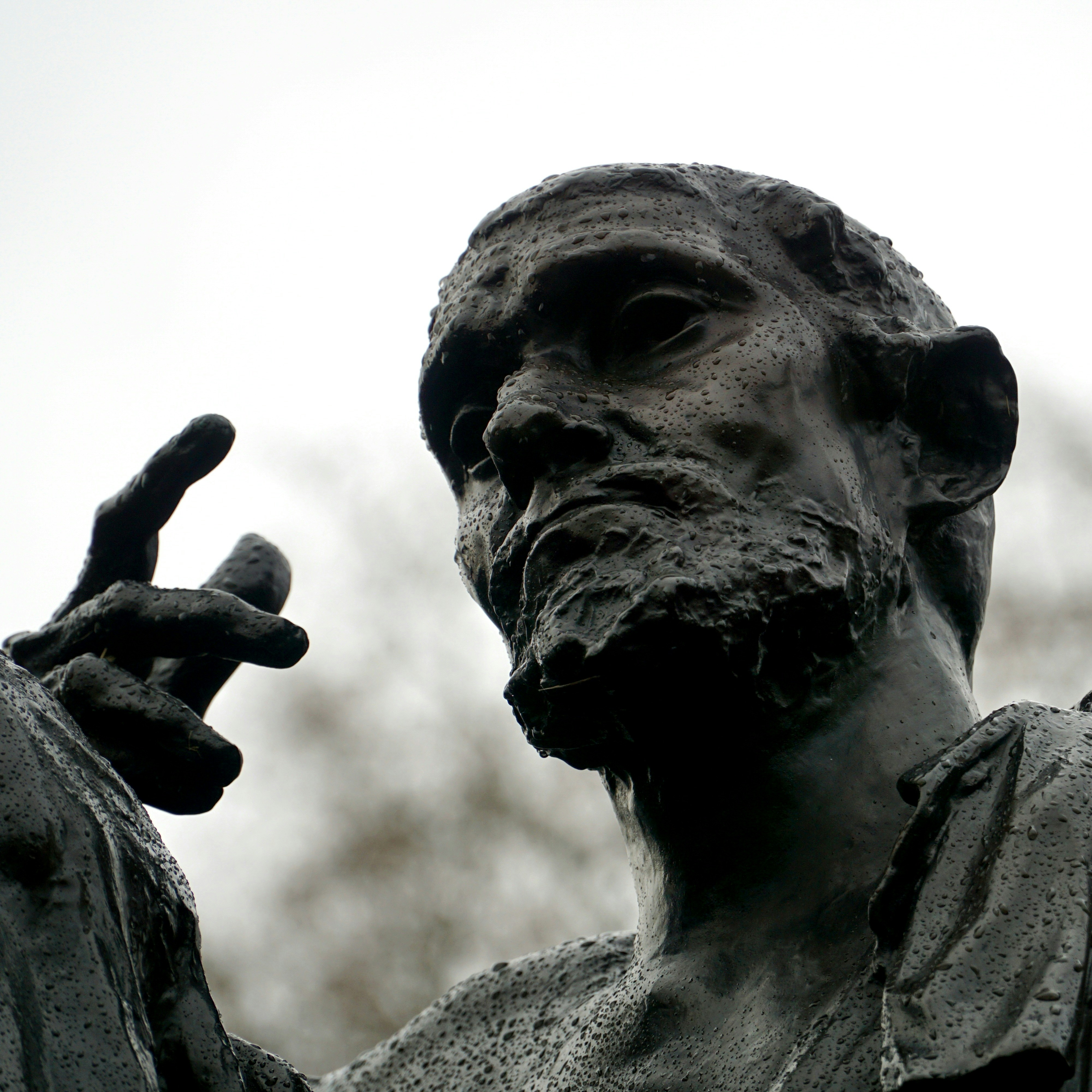 A weathered bronze statue of a bearded man looking up.
