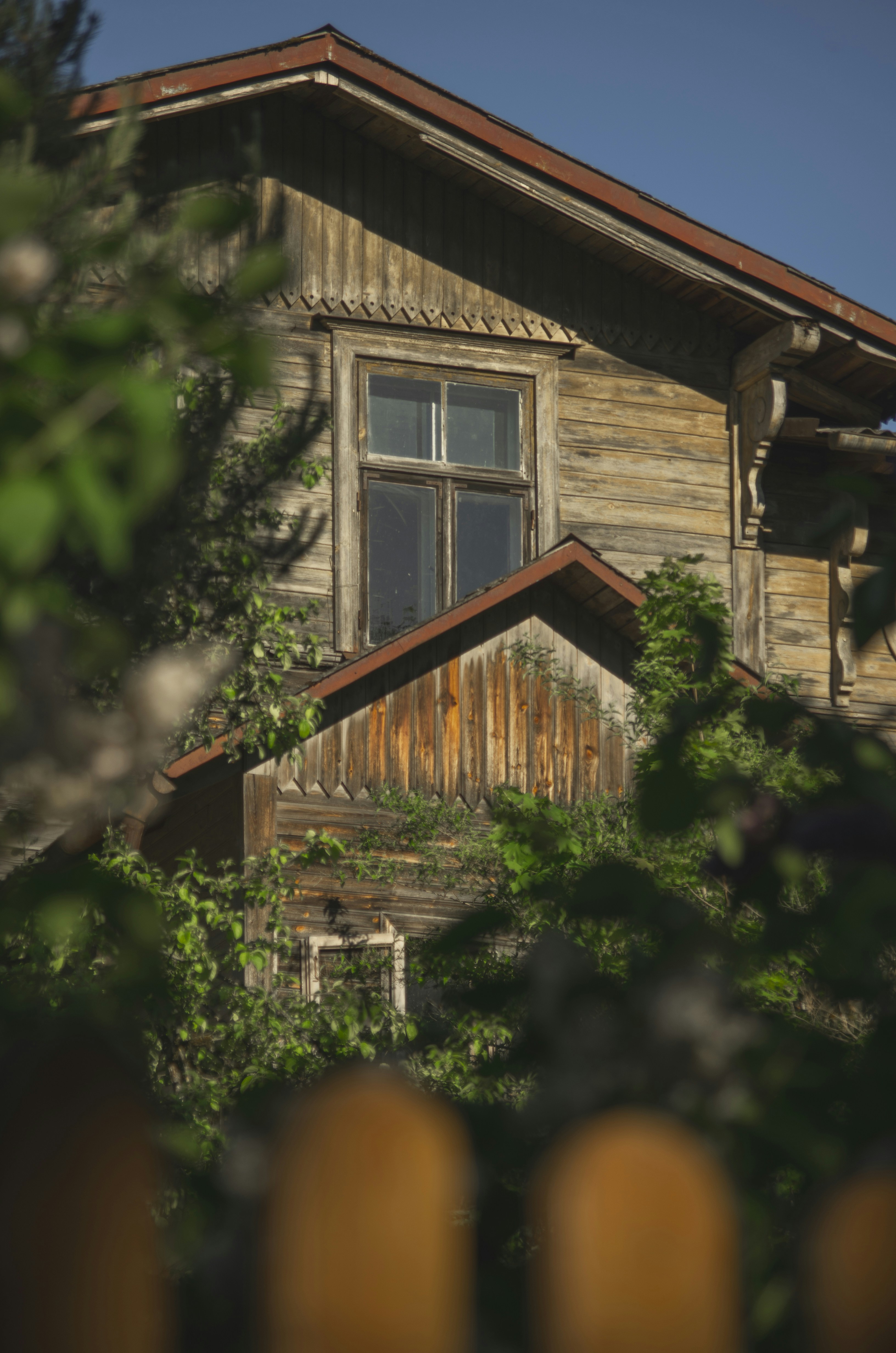 Weathered Farmhouse Gable Framed by Overgrown Garden
