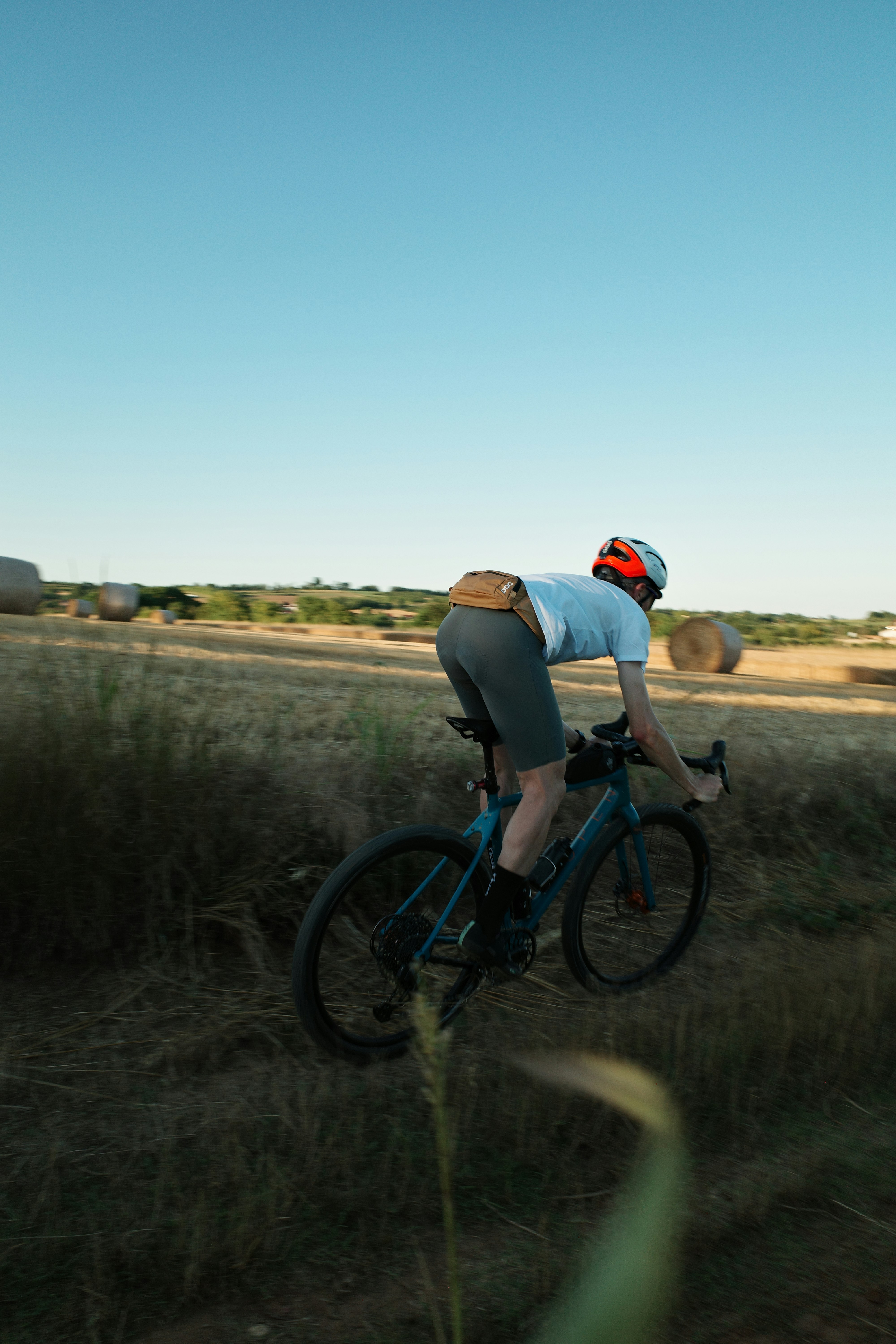 Rider in Mid-Turn: A Blue Road Bike Through Open Fields
