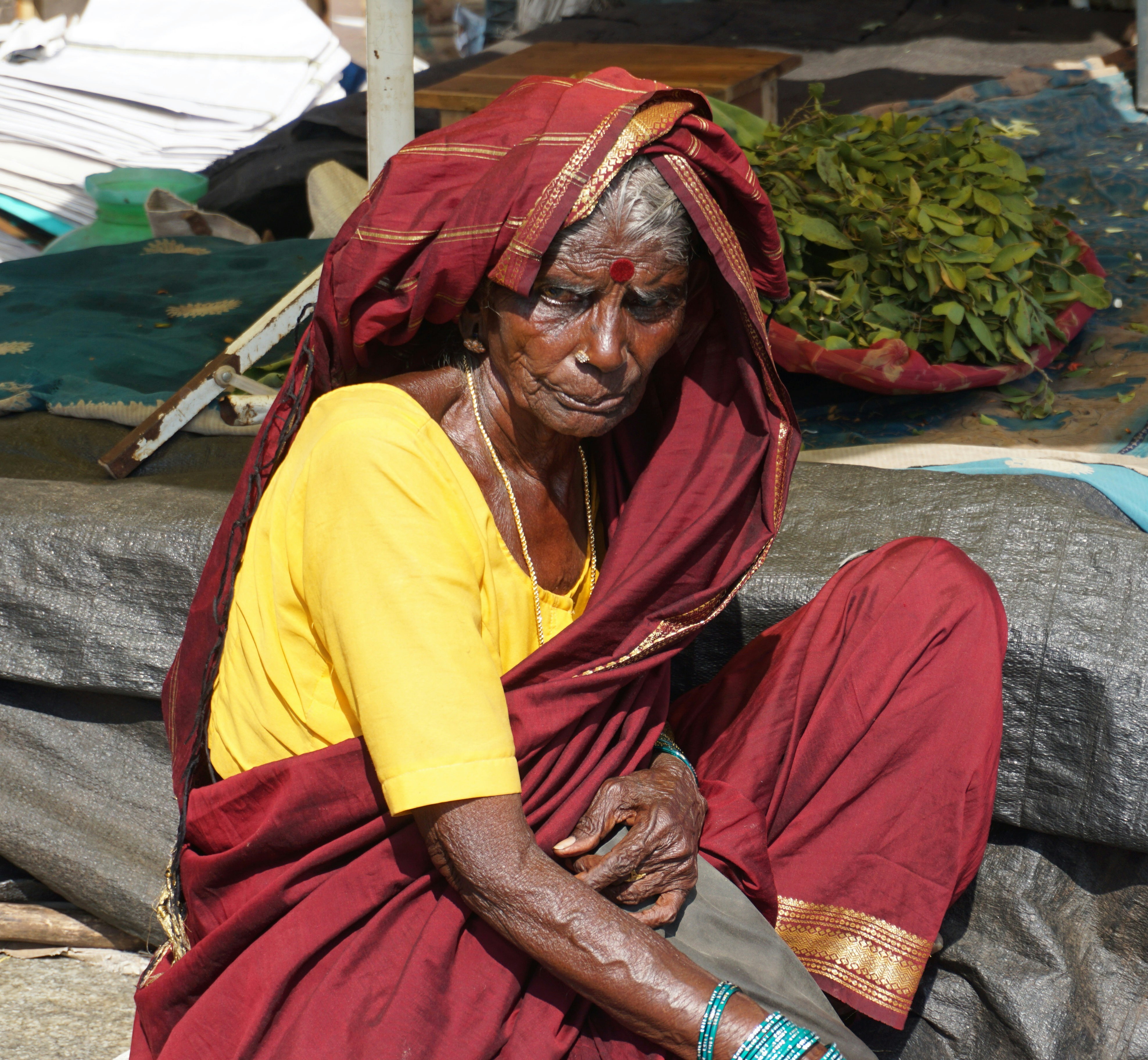 Wrapped in Color: Elderly Vendor in Ayurveda Market Colors