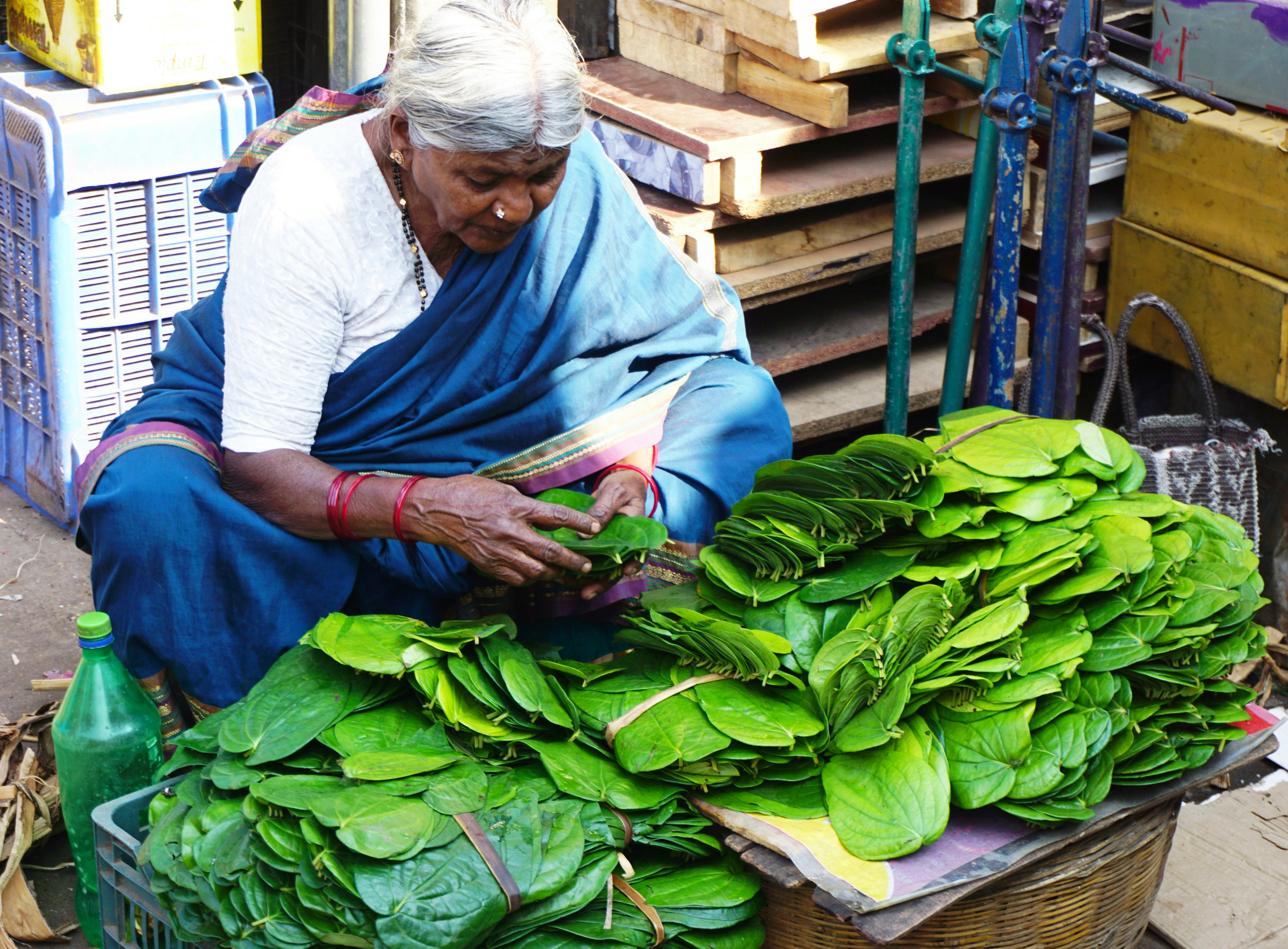 Hands at Work: An Elderly Vendor Preparing Leafy Baskets for Market