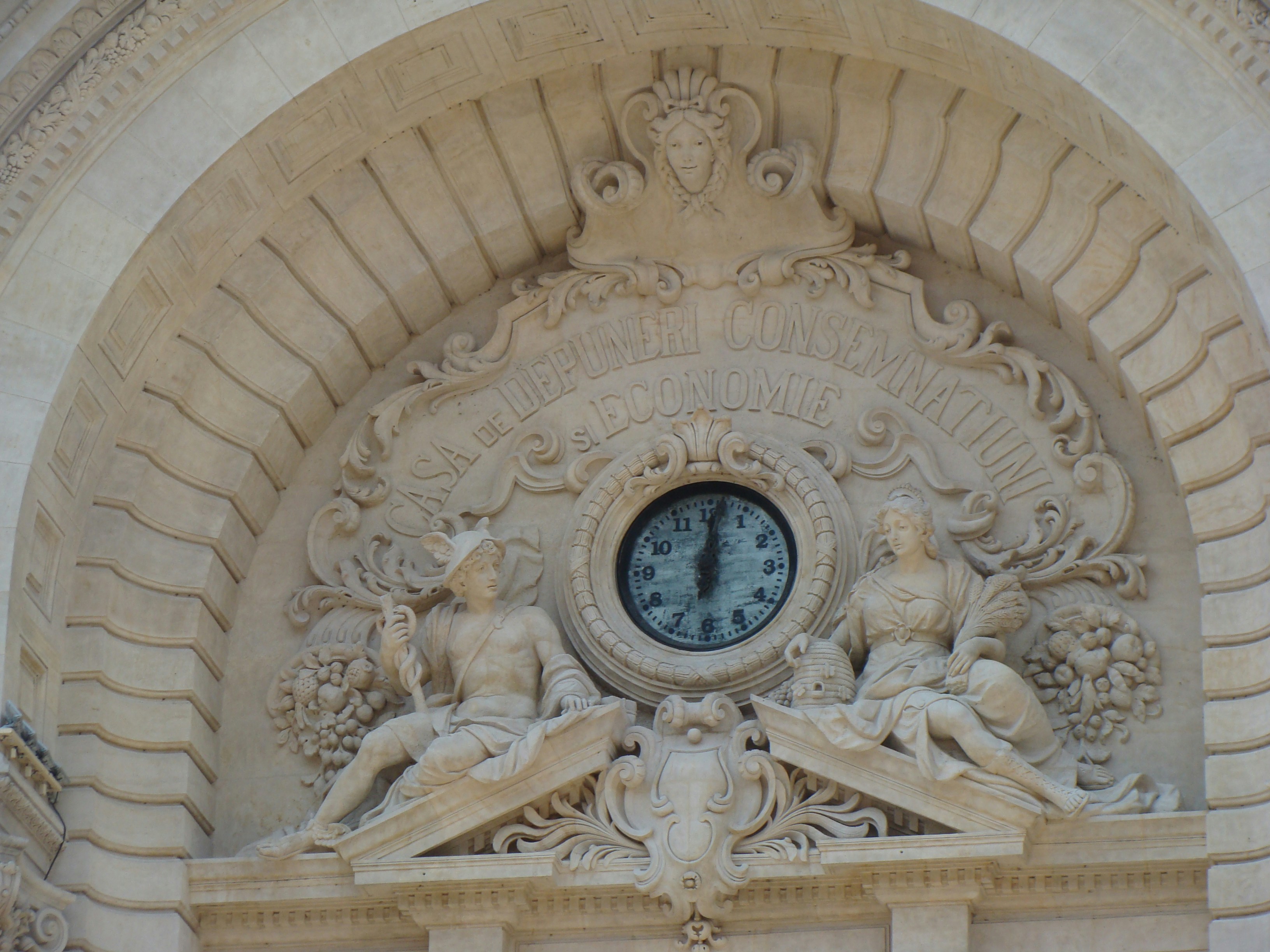 Intricately carved stone clock facade with regal figures and decorative motifs surrounding a central clock.