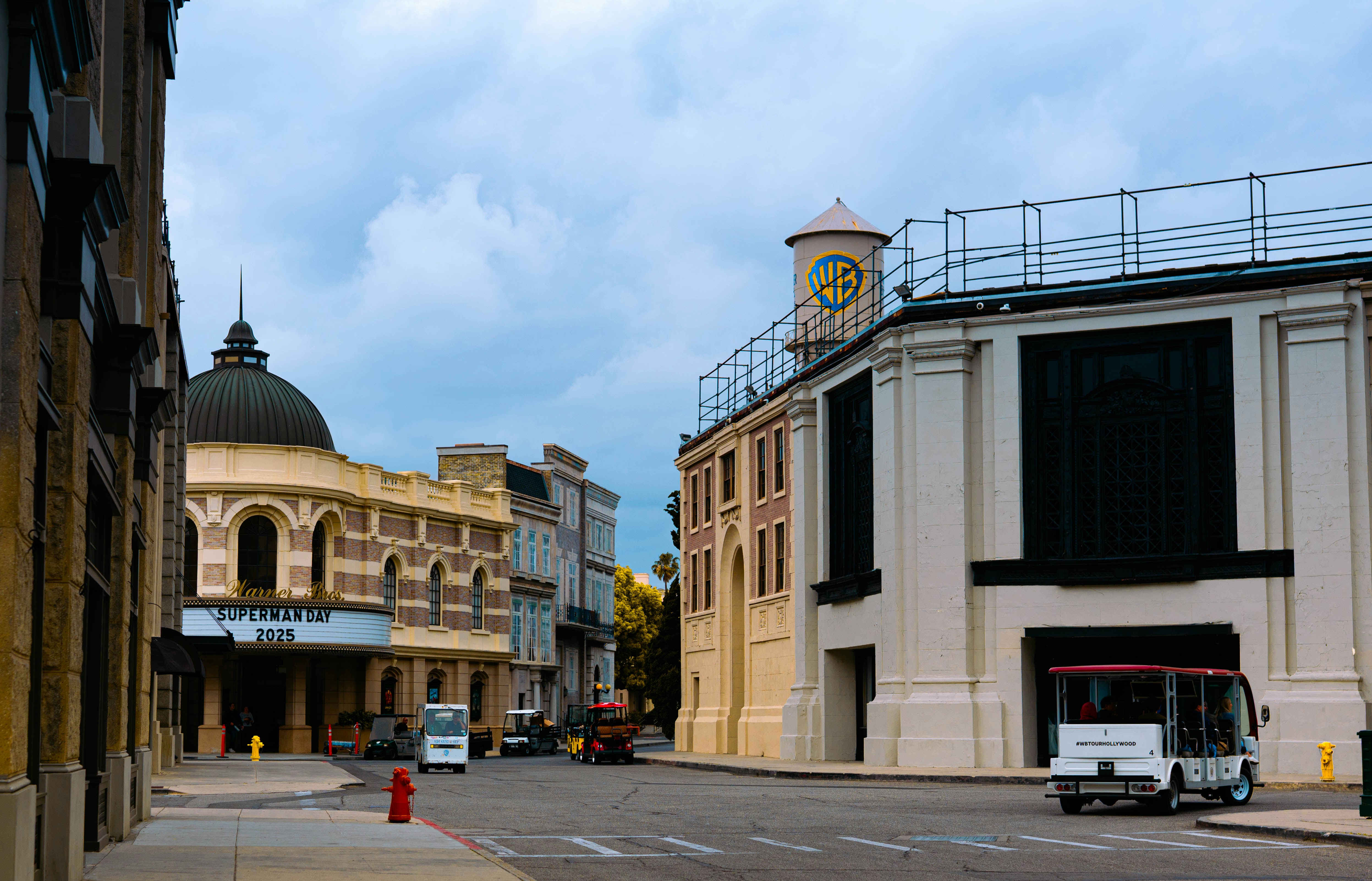 Wide street with vintage buildings and a small bus in the foreground; a gentle blue sky overhead, capturing a calm urban scene.