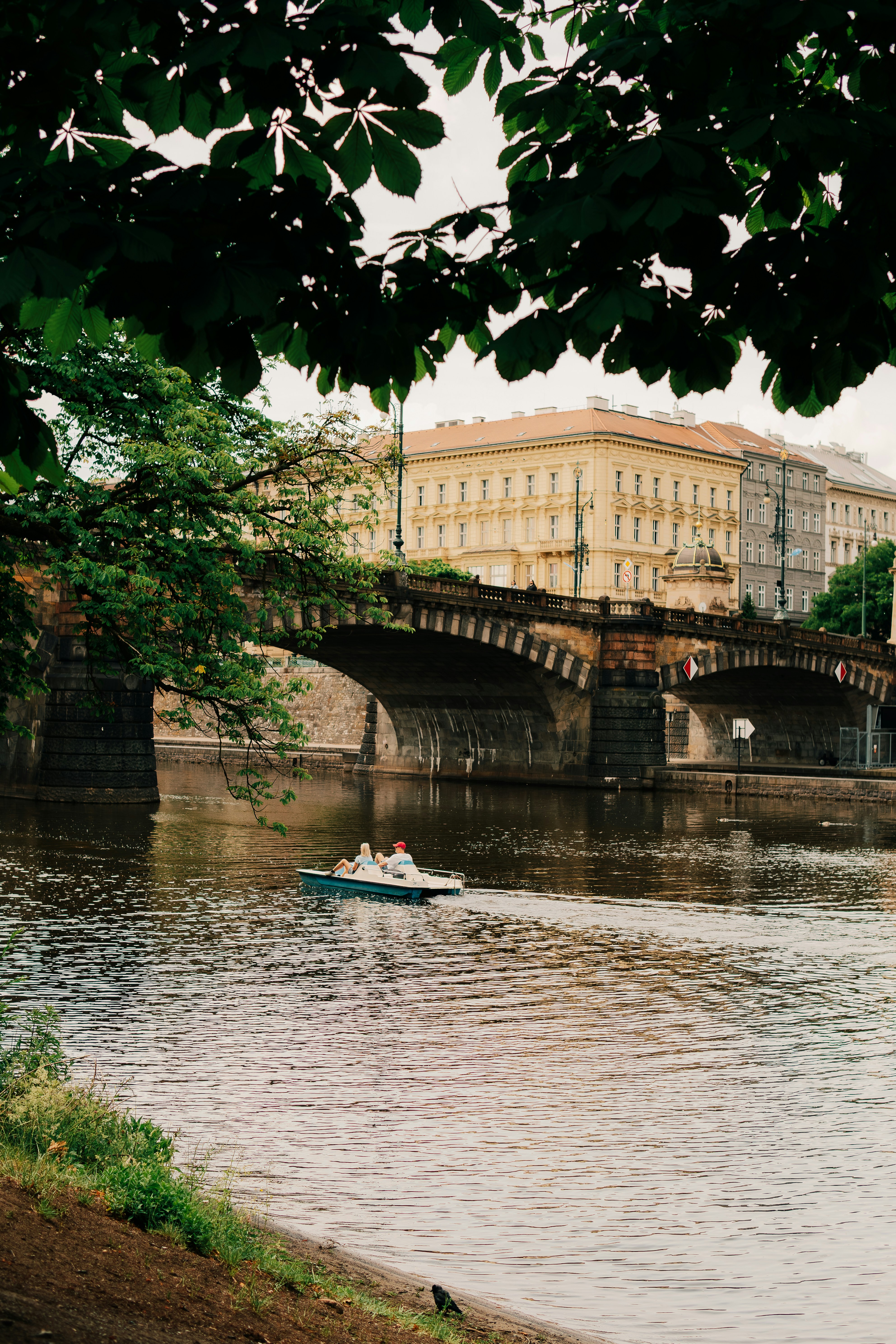 Boat on the River Beneath a Historic City Bridge