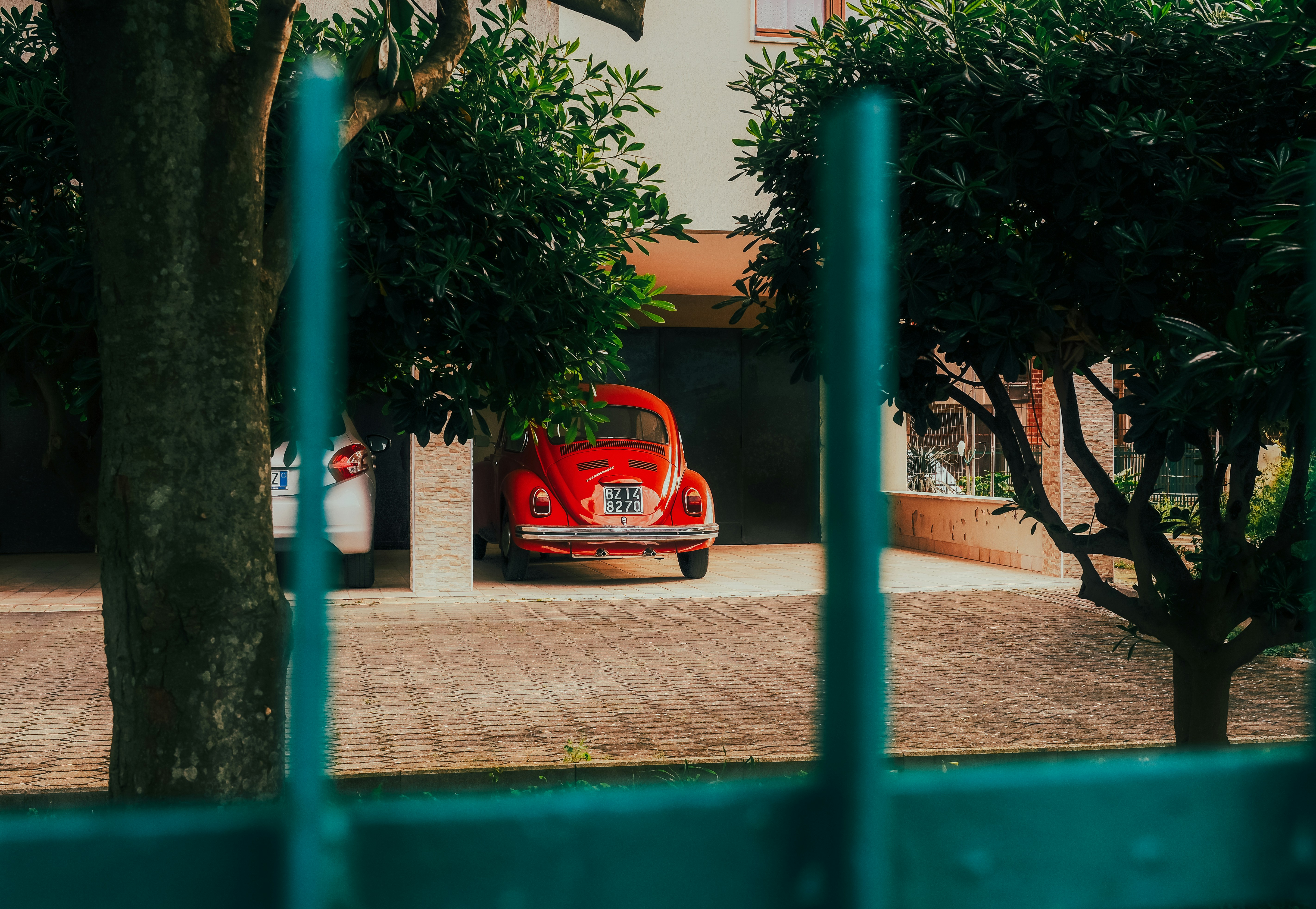 Red Classic in the Courtyard: A Hidden Car Between Trees