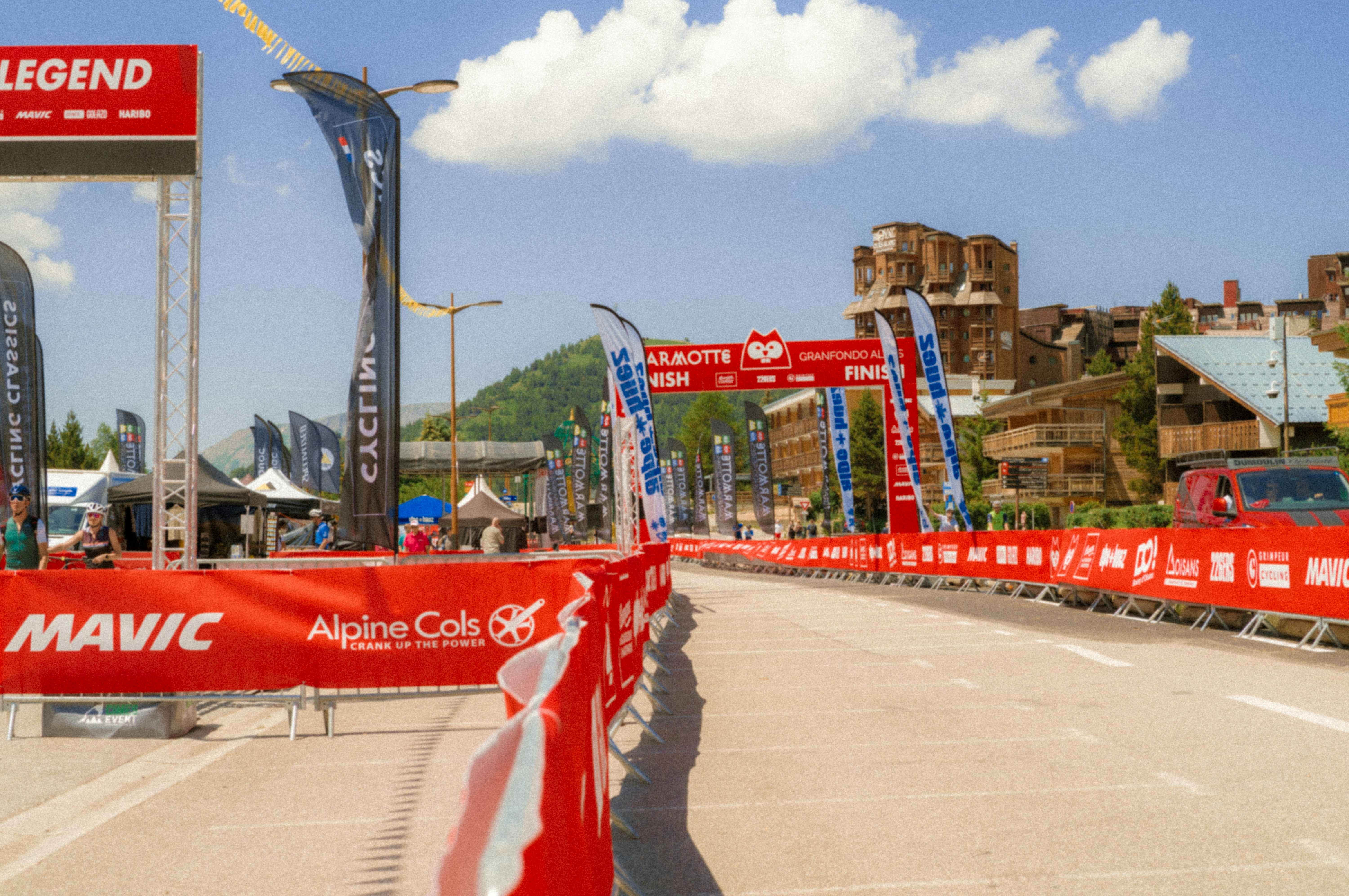 Finish Line Archway: Red Barricades and Flags Framing a Sunlit Race Street