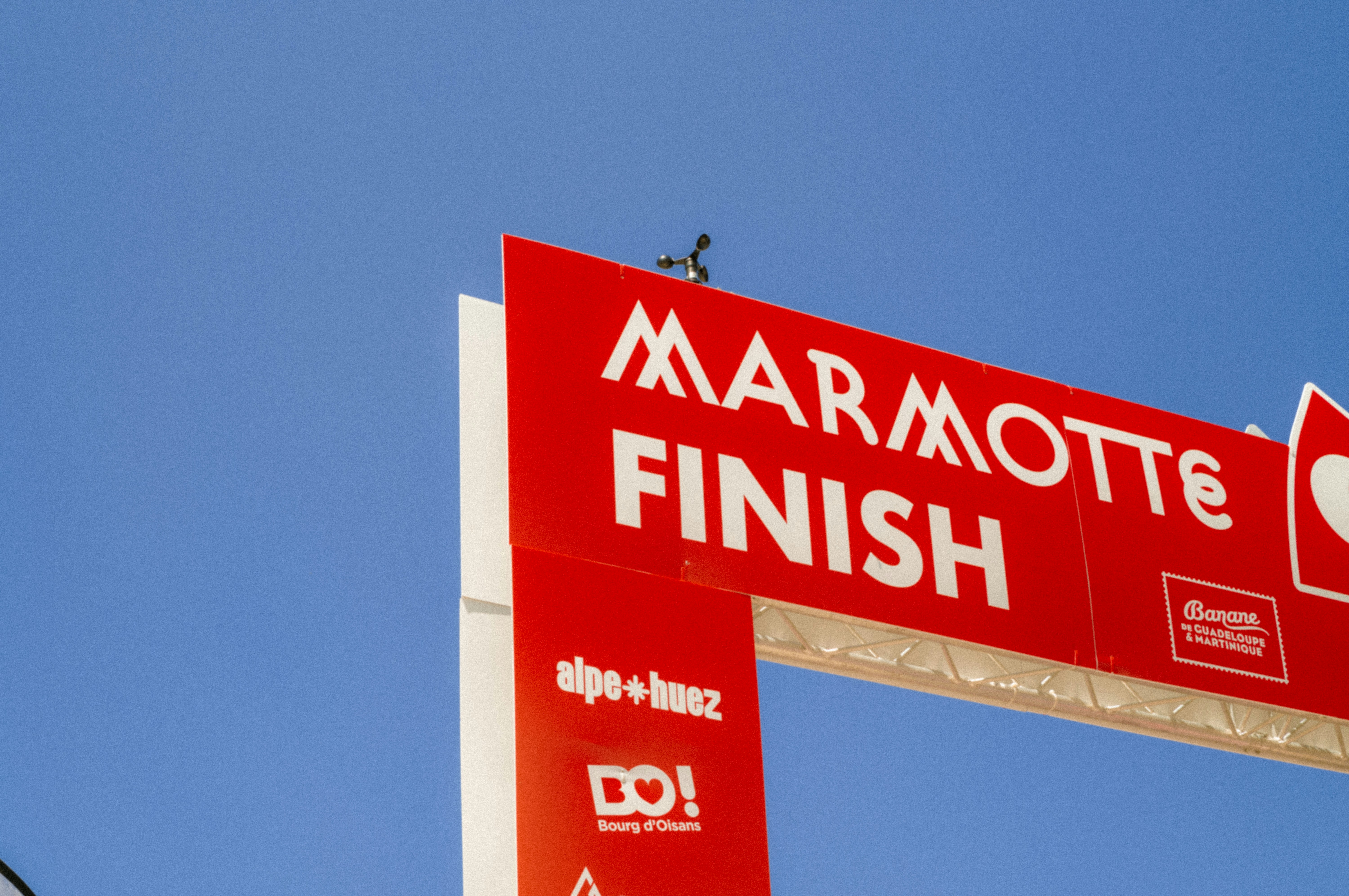 Finish Line Over the Blue: Minted Red Arch Stretches Across a Clear Sky