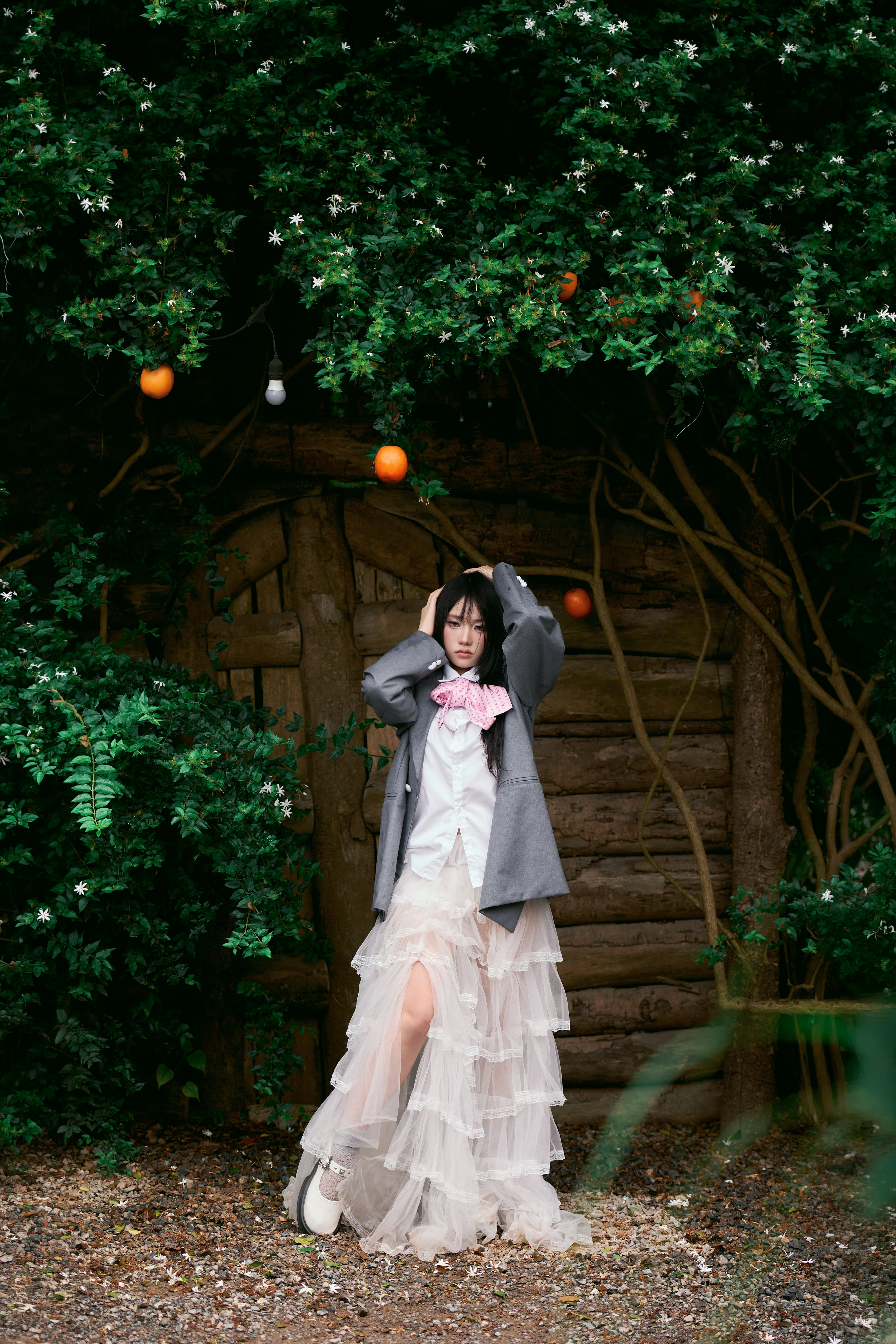 Frilled Diorama: A Young Woman in Pale Layers Beneath an Orchard of Orange Ornaments