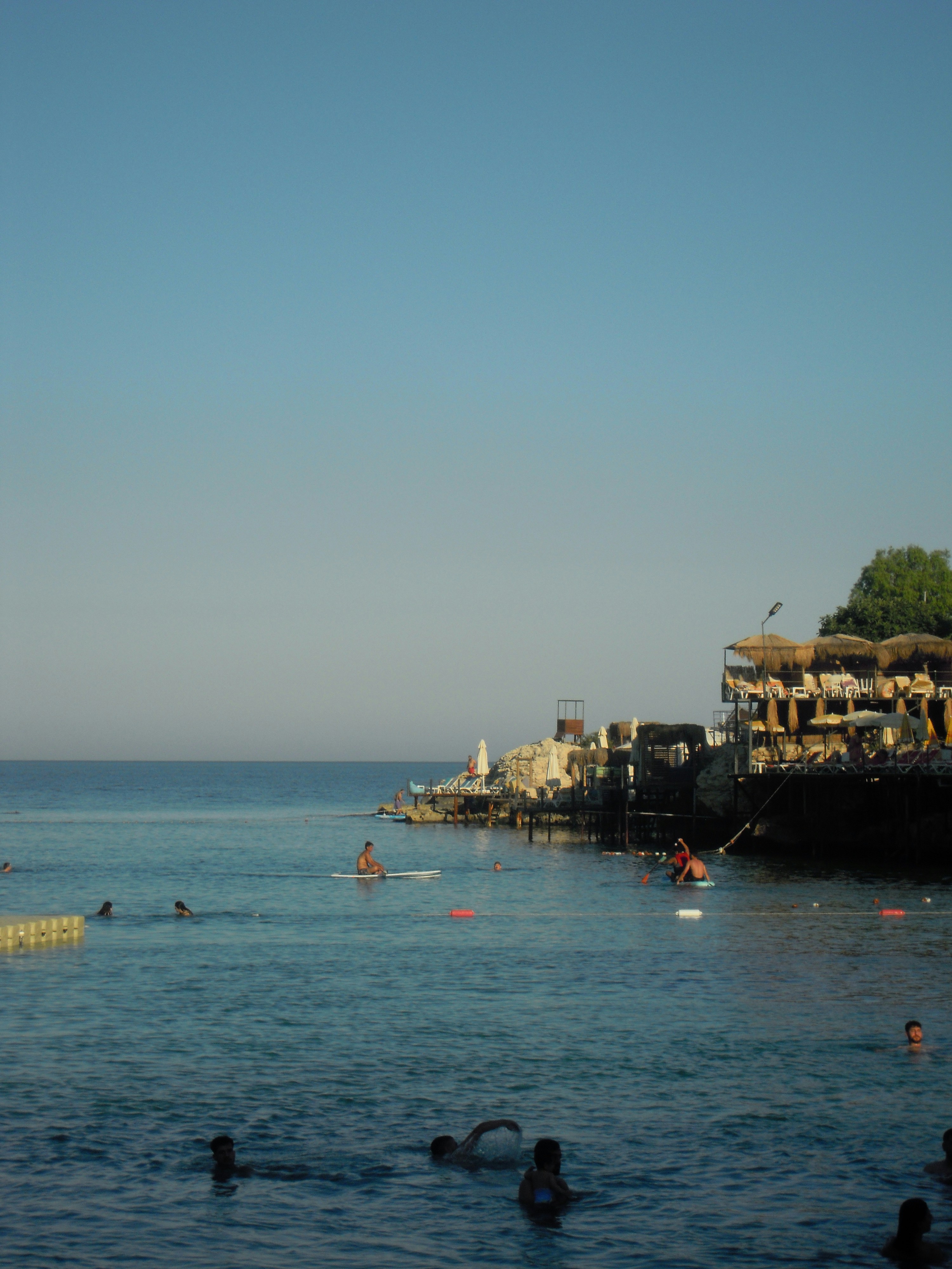 Sunlit Seaside: People at Play by a Village Pier