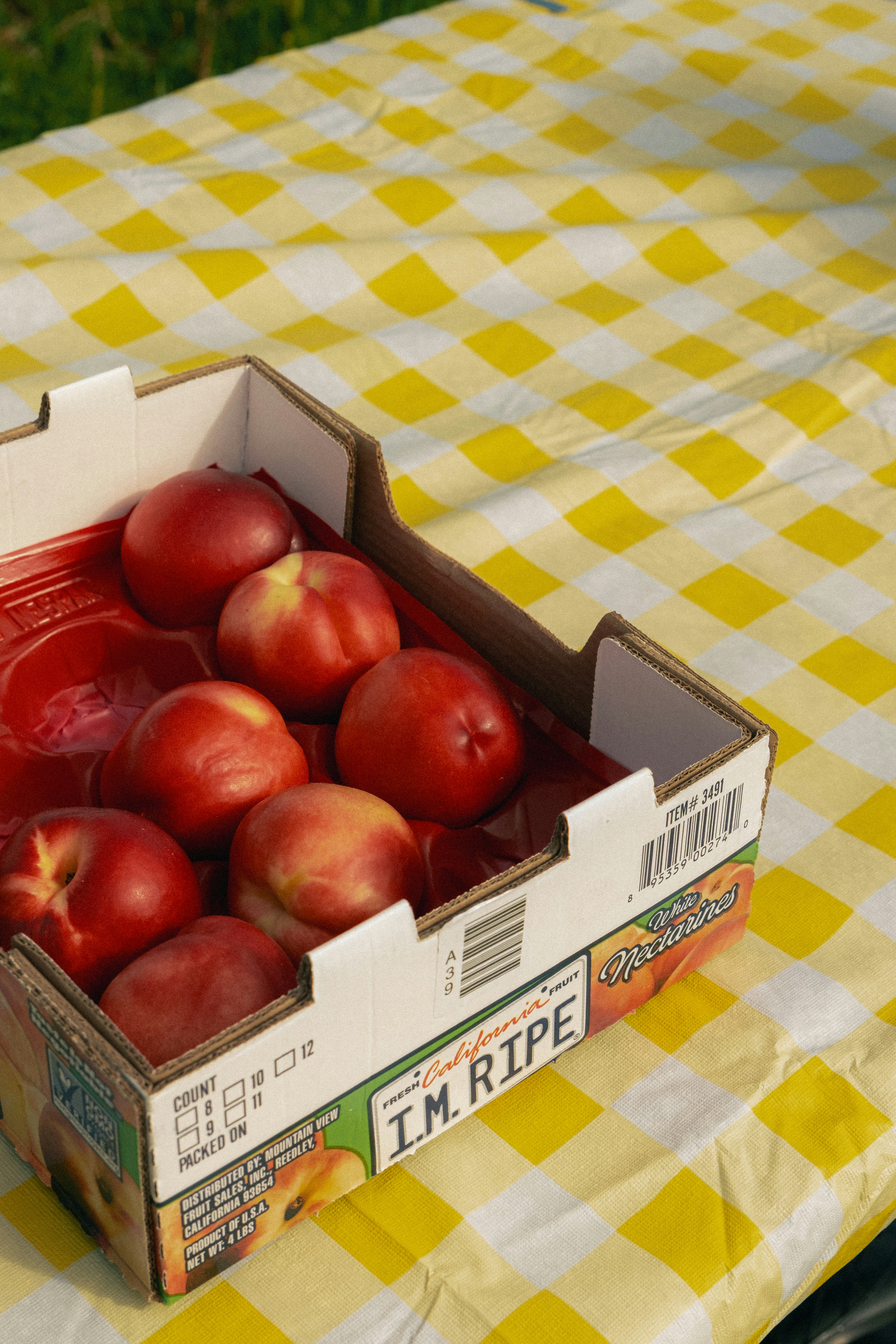 Box of Nectarines on a Yellow-Checked Tablecloth