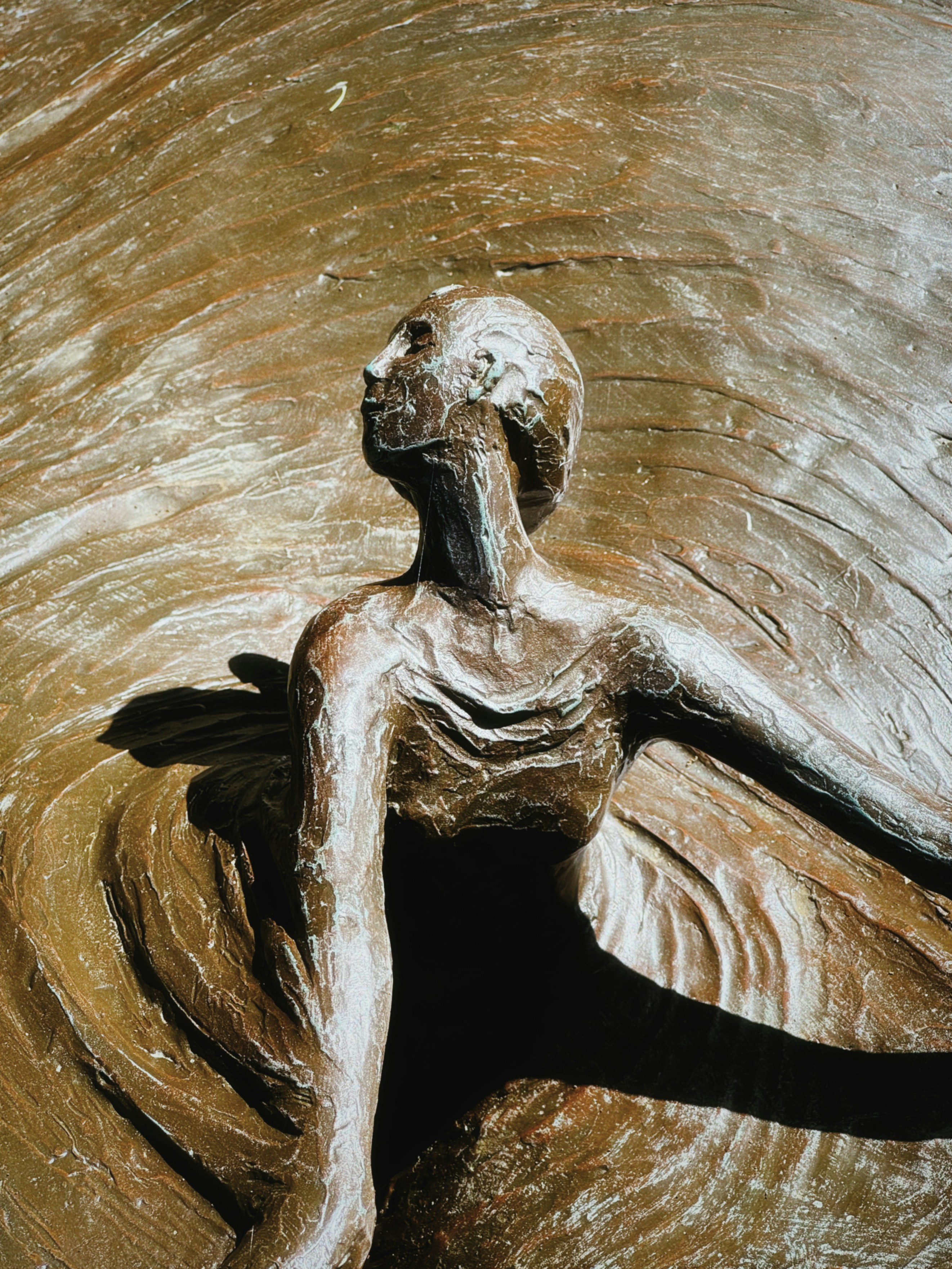 Swirled Shards: A Bronze Figure Emerges from the Spiral