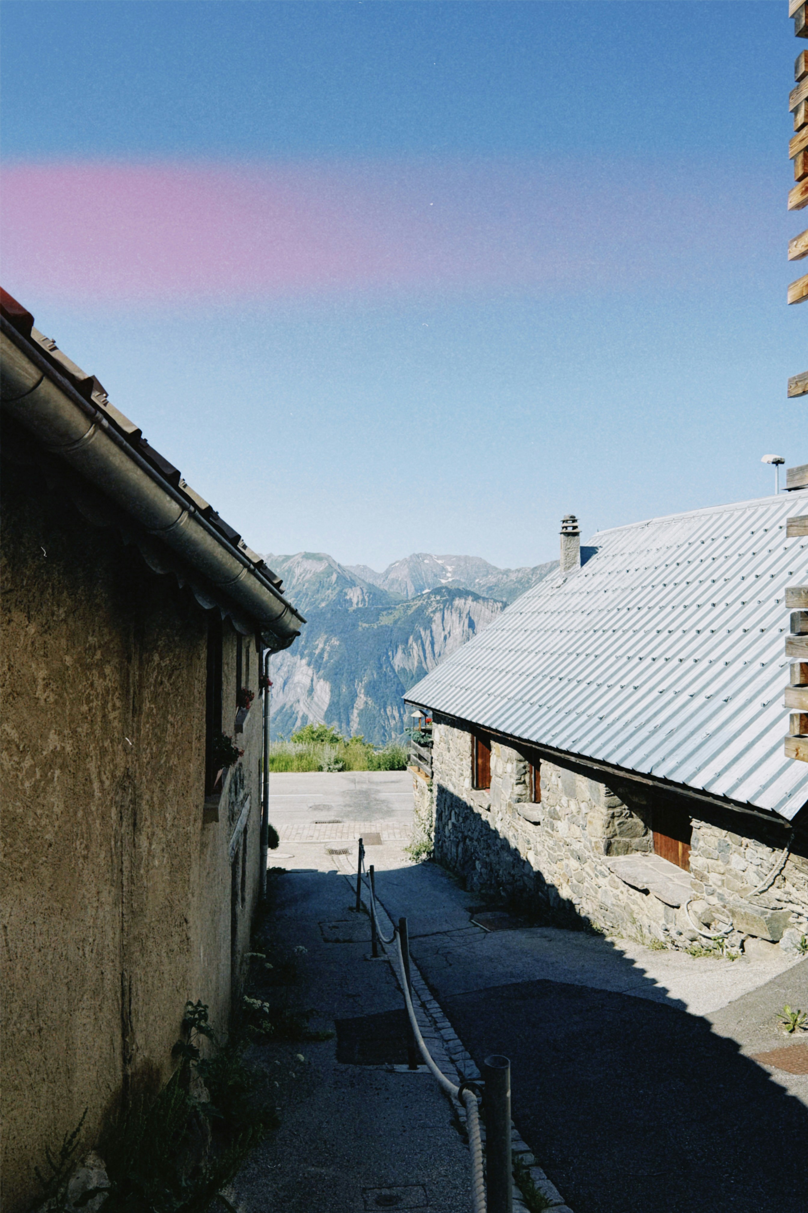 Alpine Alley: A Winding Path Between Stone Roofs with Mountain Backdrop