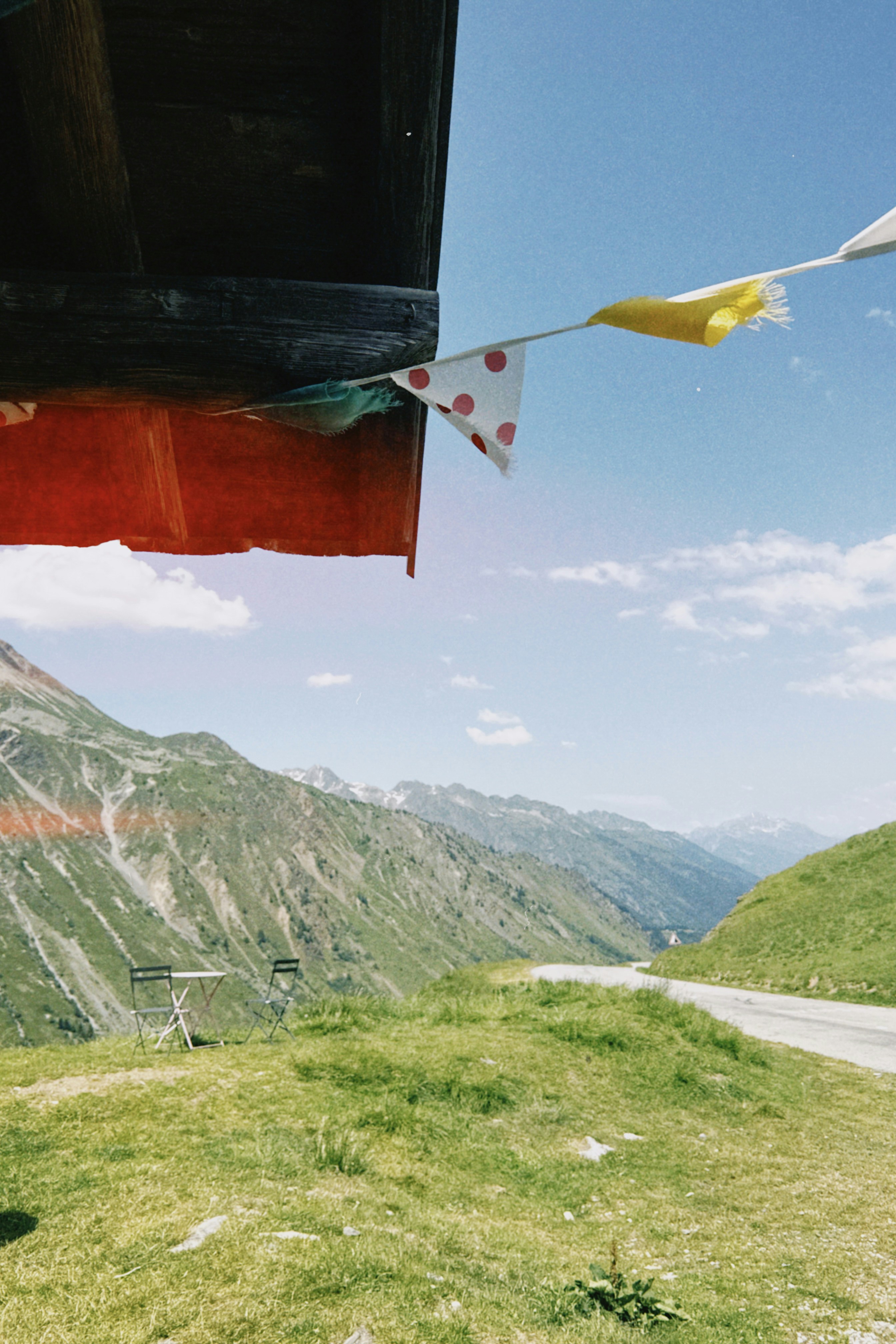 Alpine flags flutter over a sunlit hillside cafe