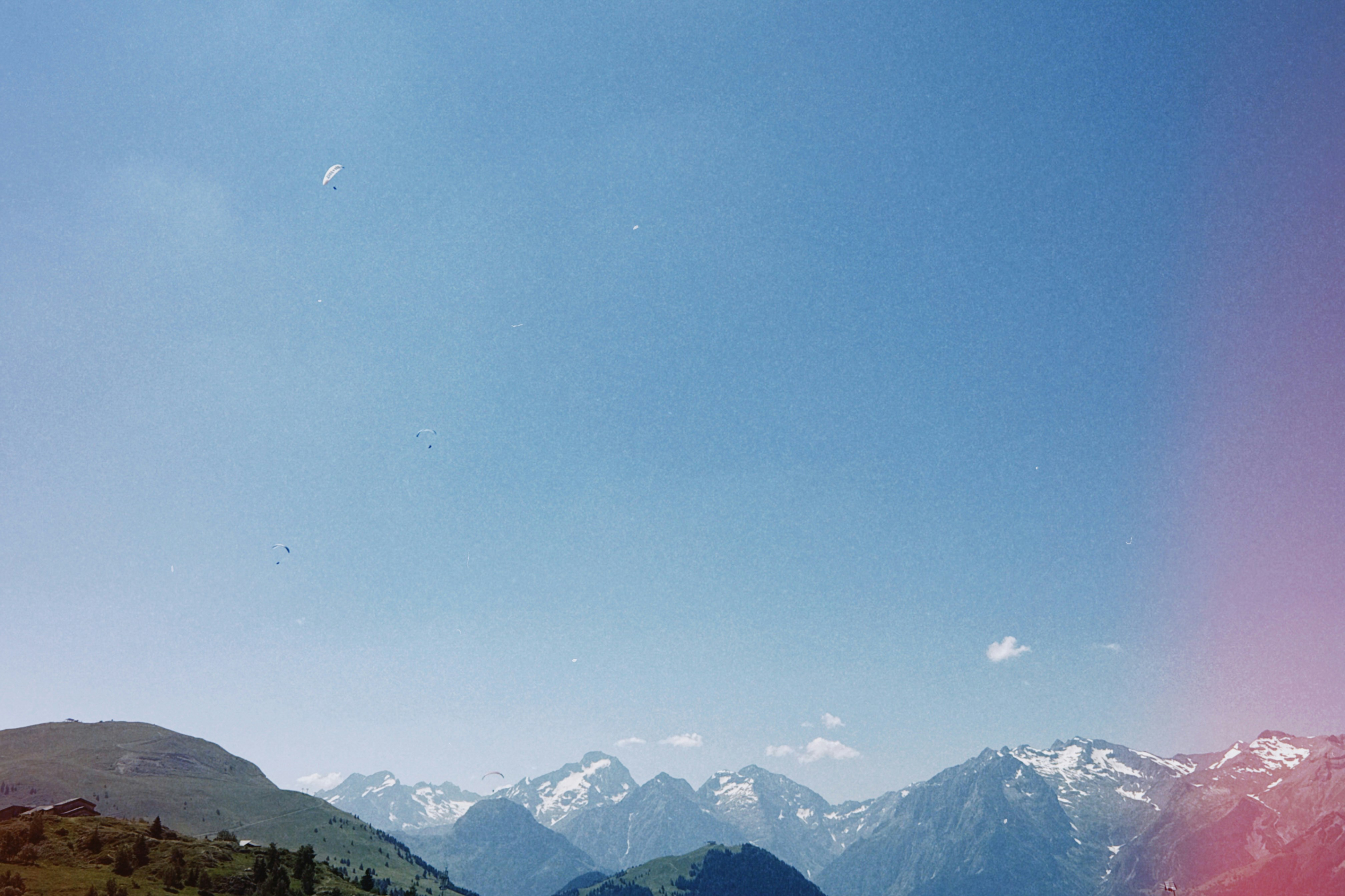 Snow-capped valley under a clear blue sky with a soft pink light spill